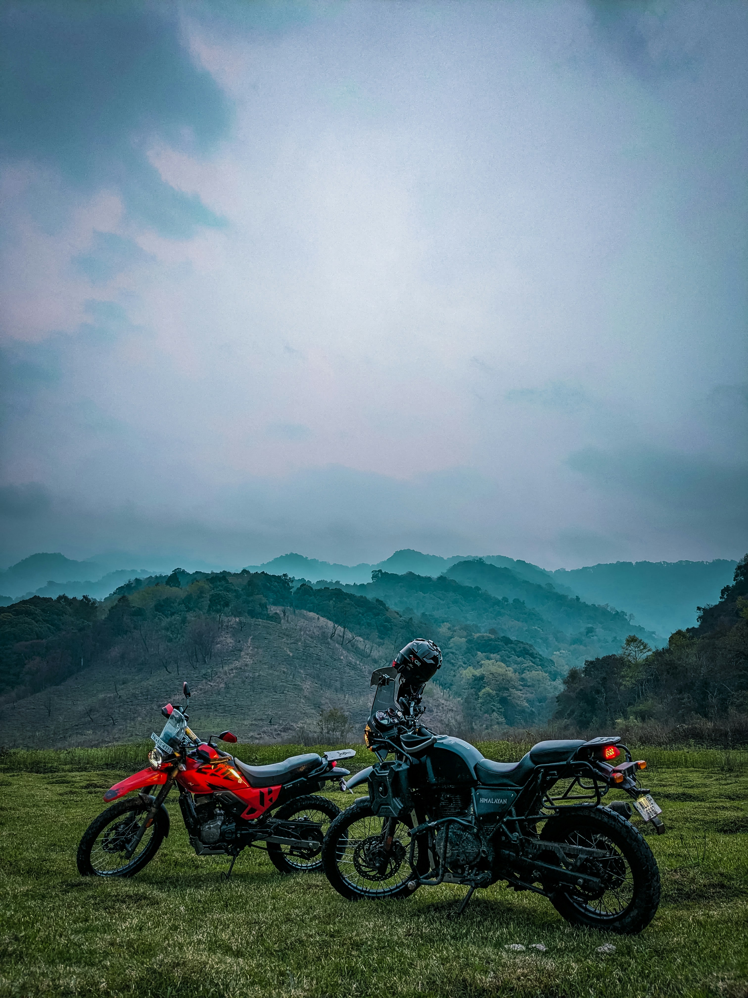A couple of motorcycles parked on top of a lush green field photo ...