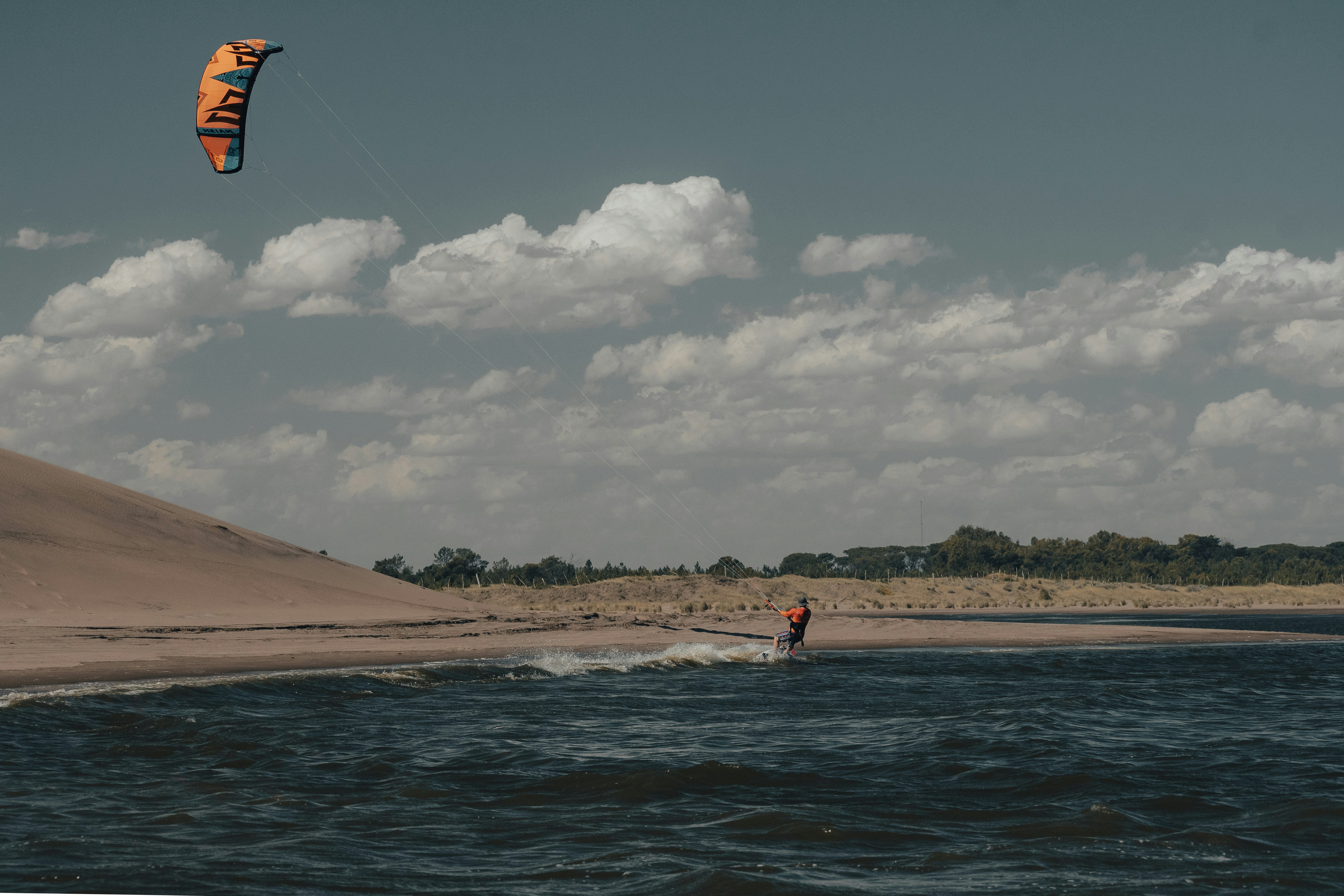 Orange Kite, Quiet Break: A Surfer Skims the Shoreline