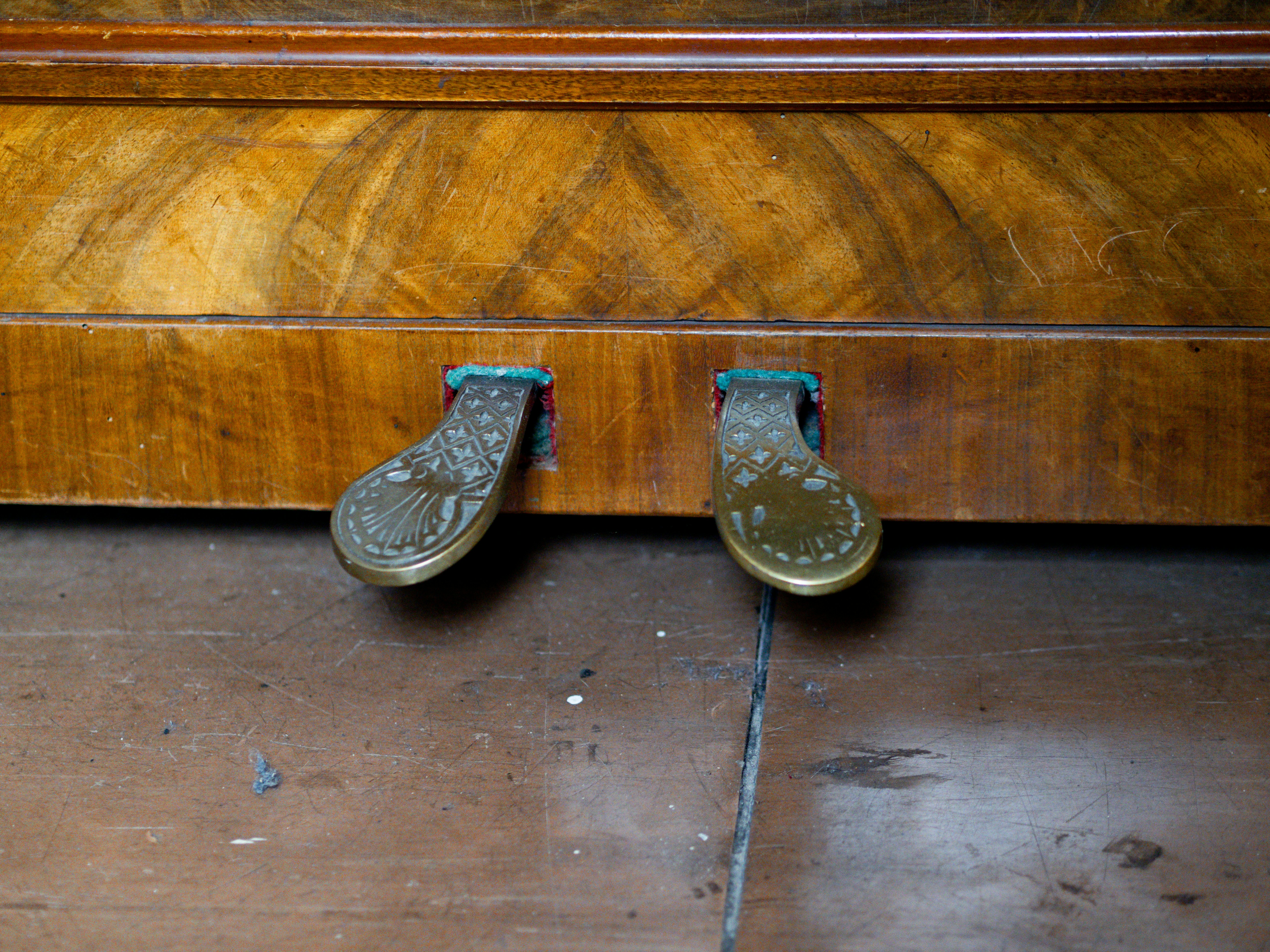 Twin Brass Pedals Beneath a Walnut Piano on a Wooden Floor