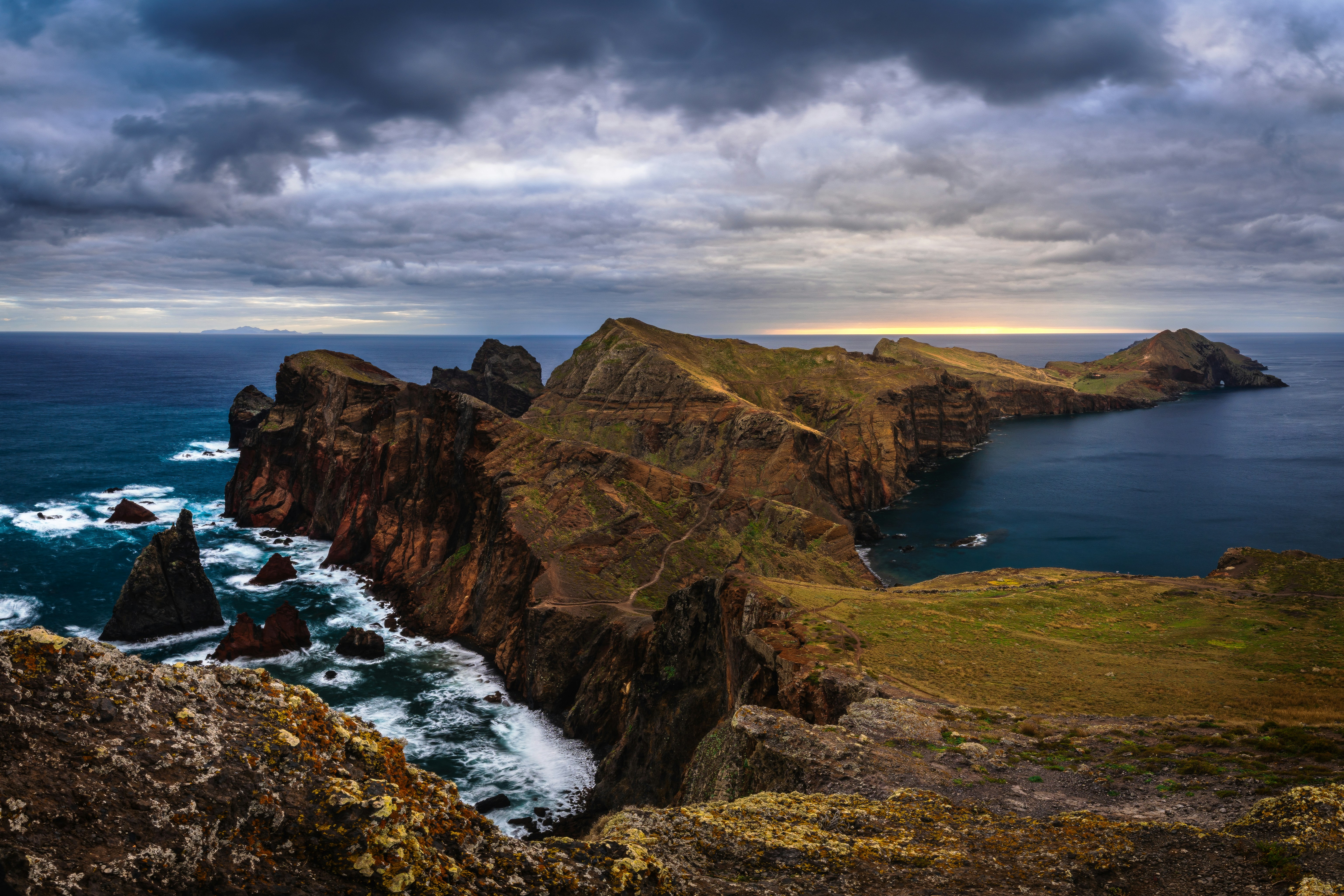 Dramatic cliffs rise above the turbulent Atlantic waves, showcasing the rugged beauty of Madeira's coastline at dusk.