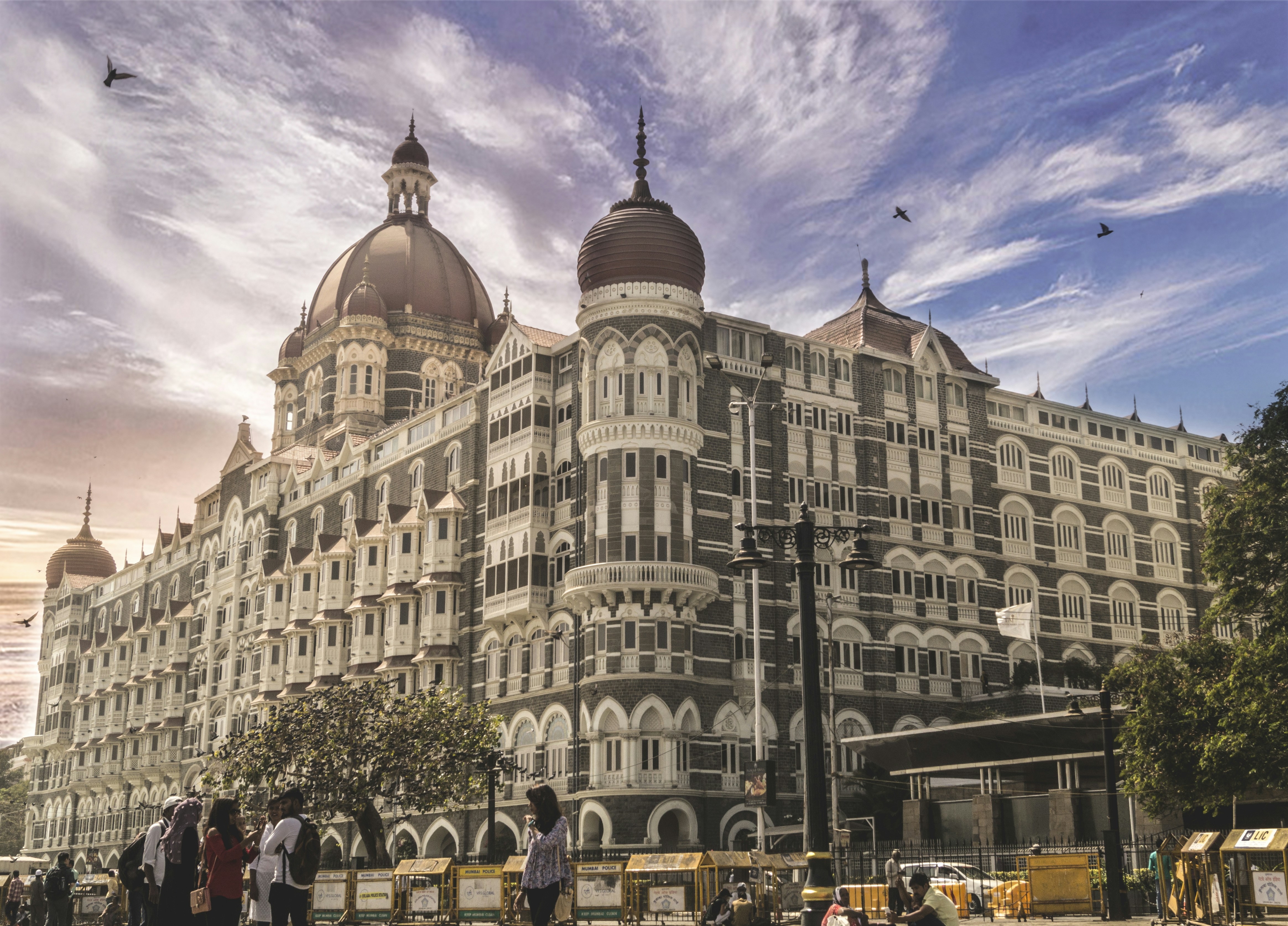 Historic hotel with domed towers under a dramatic, cloud-filled sky at sunset.