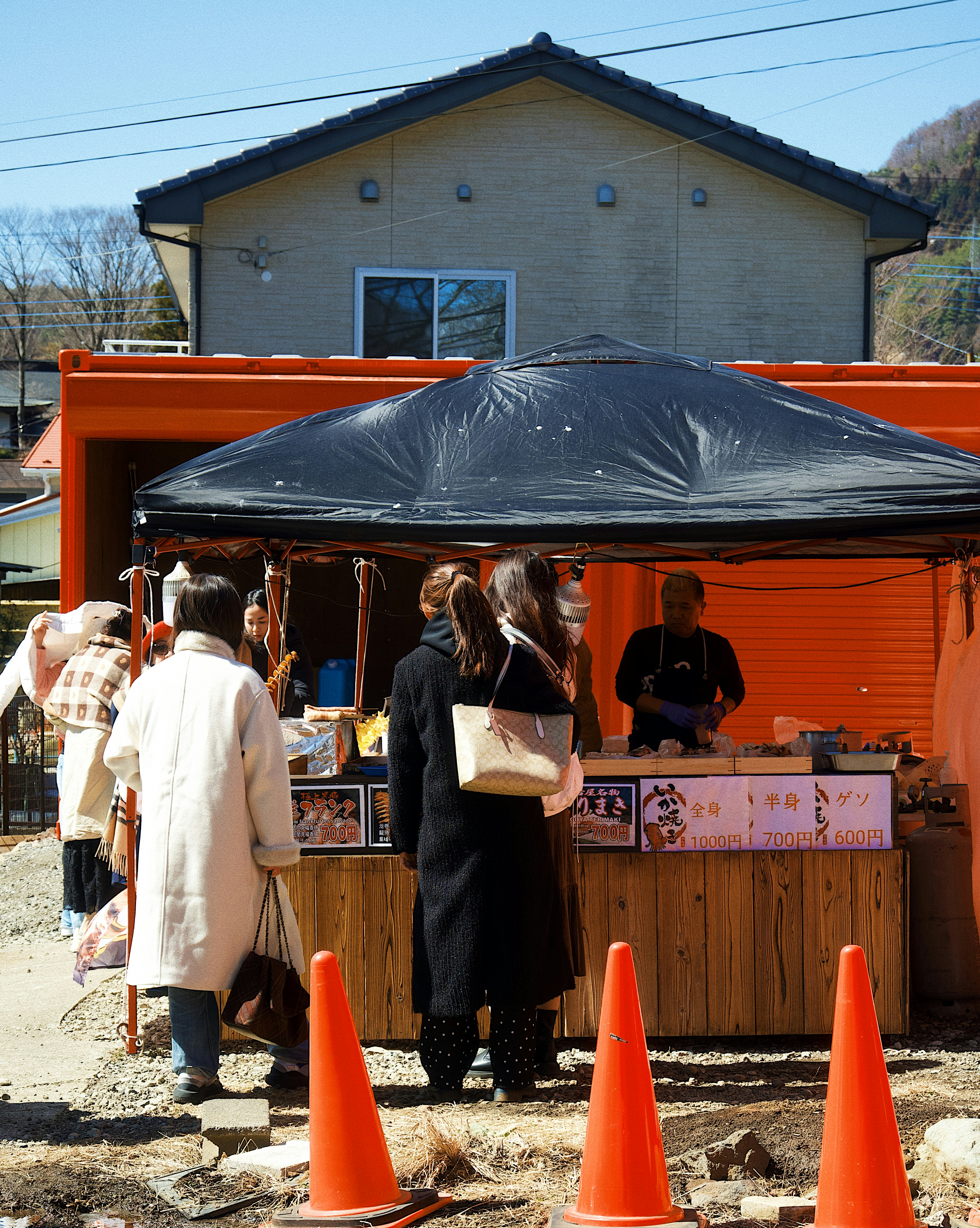 Under the Black Canopy: A Sunlit Orange Market Stall