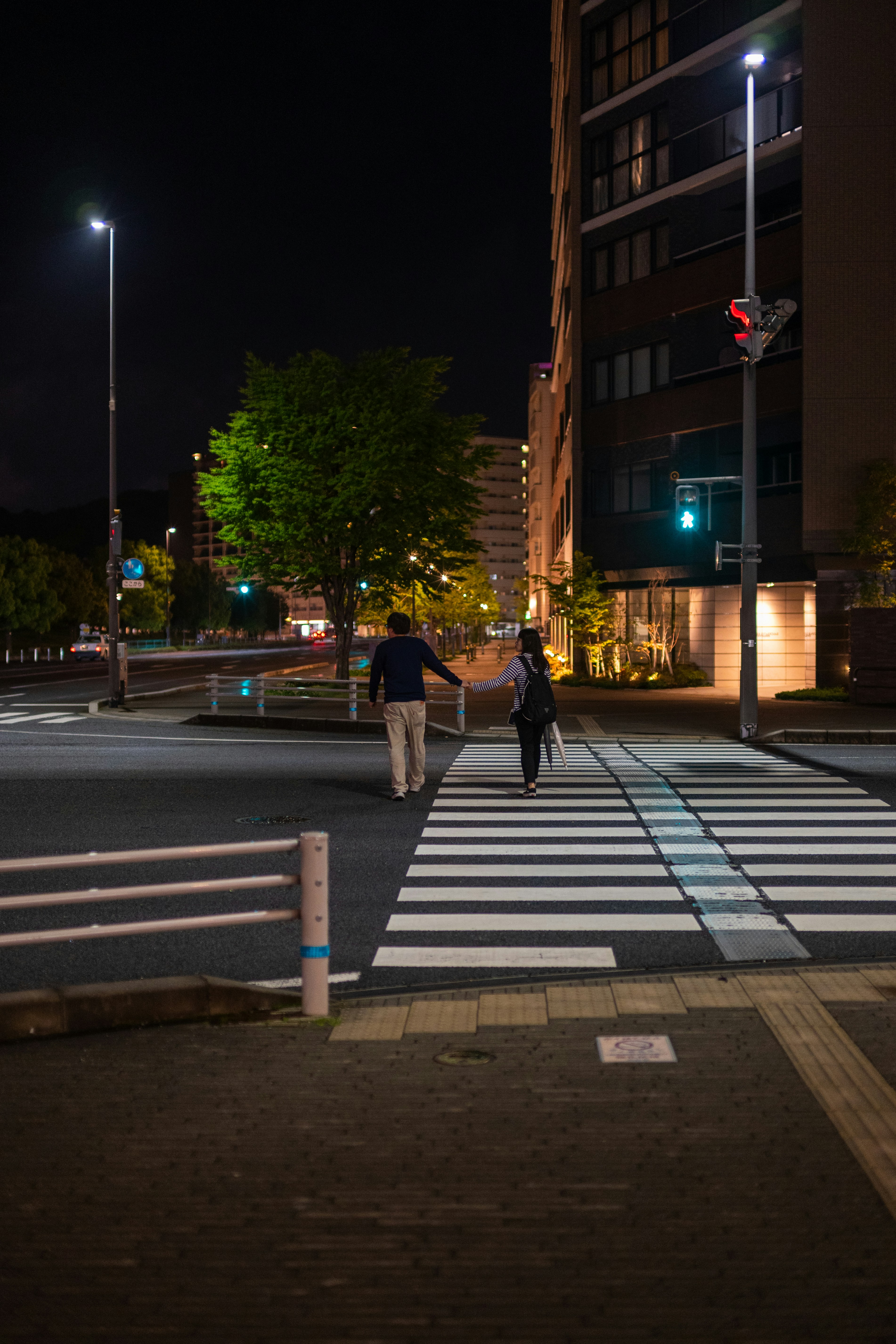 A couple of people walking across a street at night photo – Free Car ...