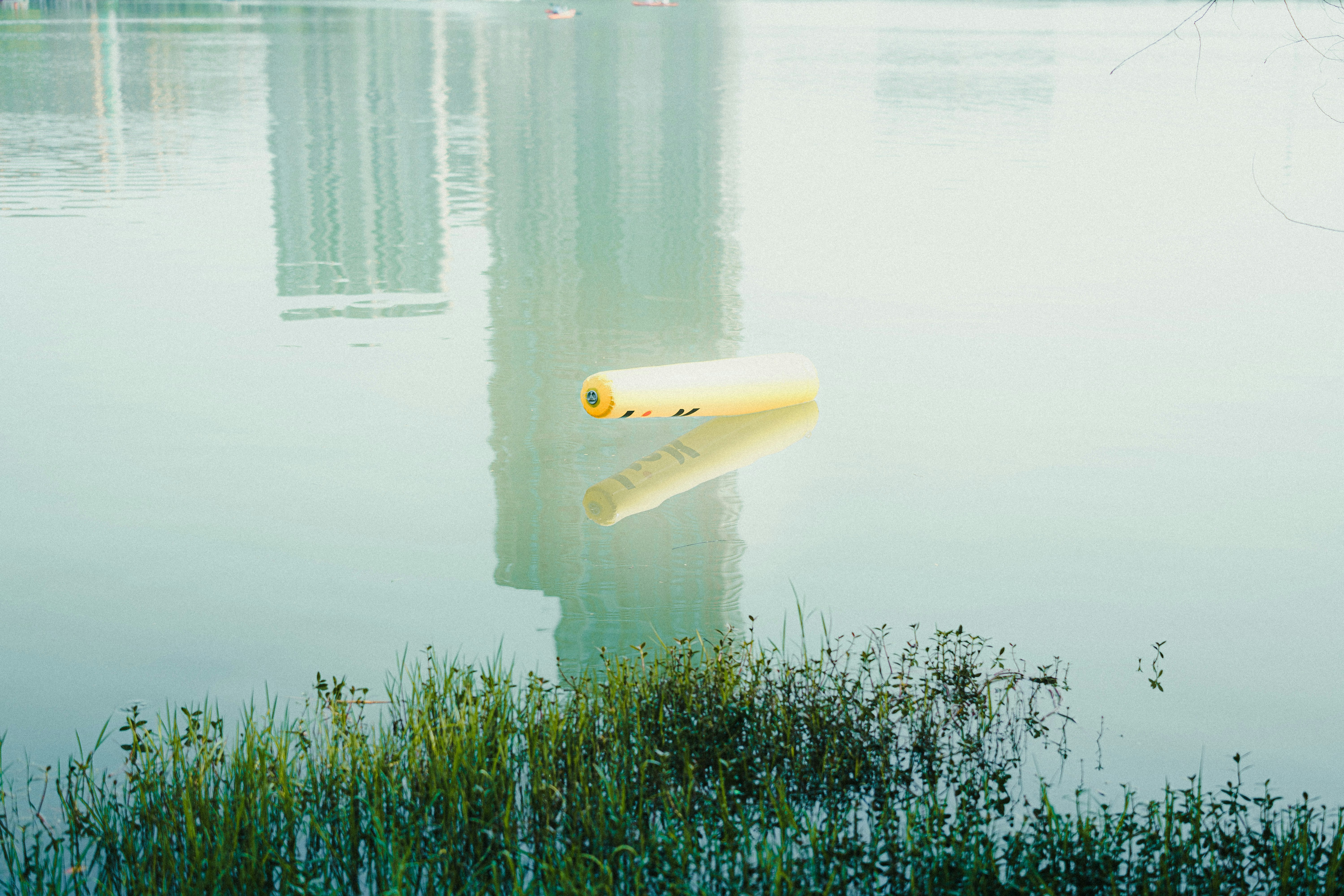 A yellow object floating on top of a body of water photo – Free Grey ...