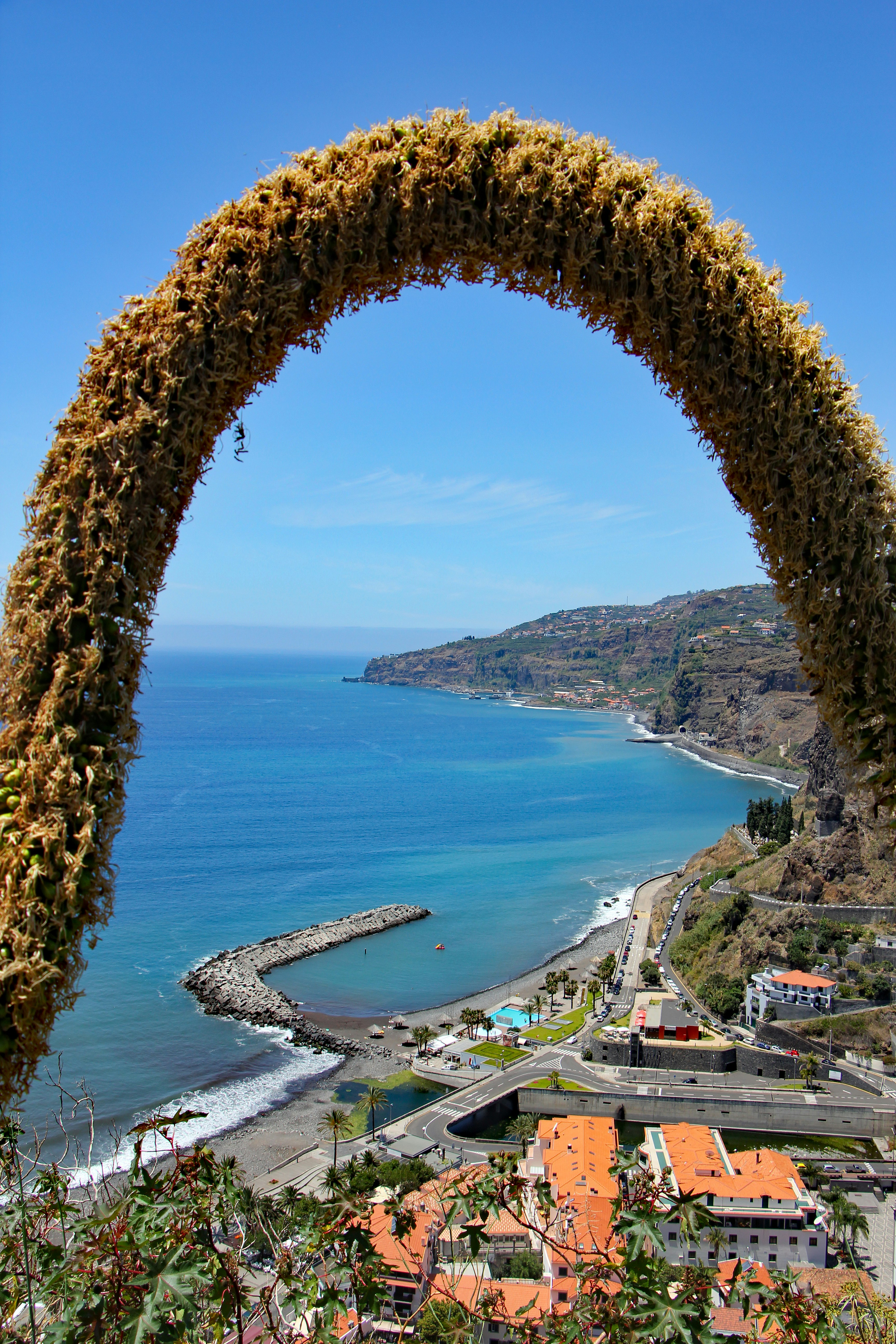 Sea Ring Overlook: A Dried-Flower Arch Framing a Cliffside Town