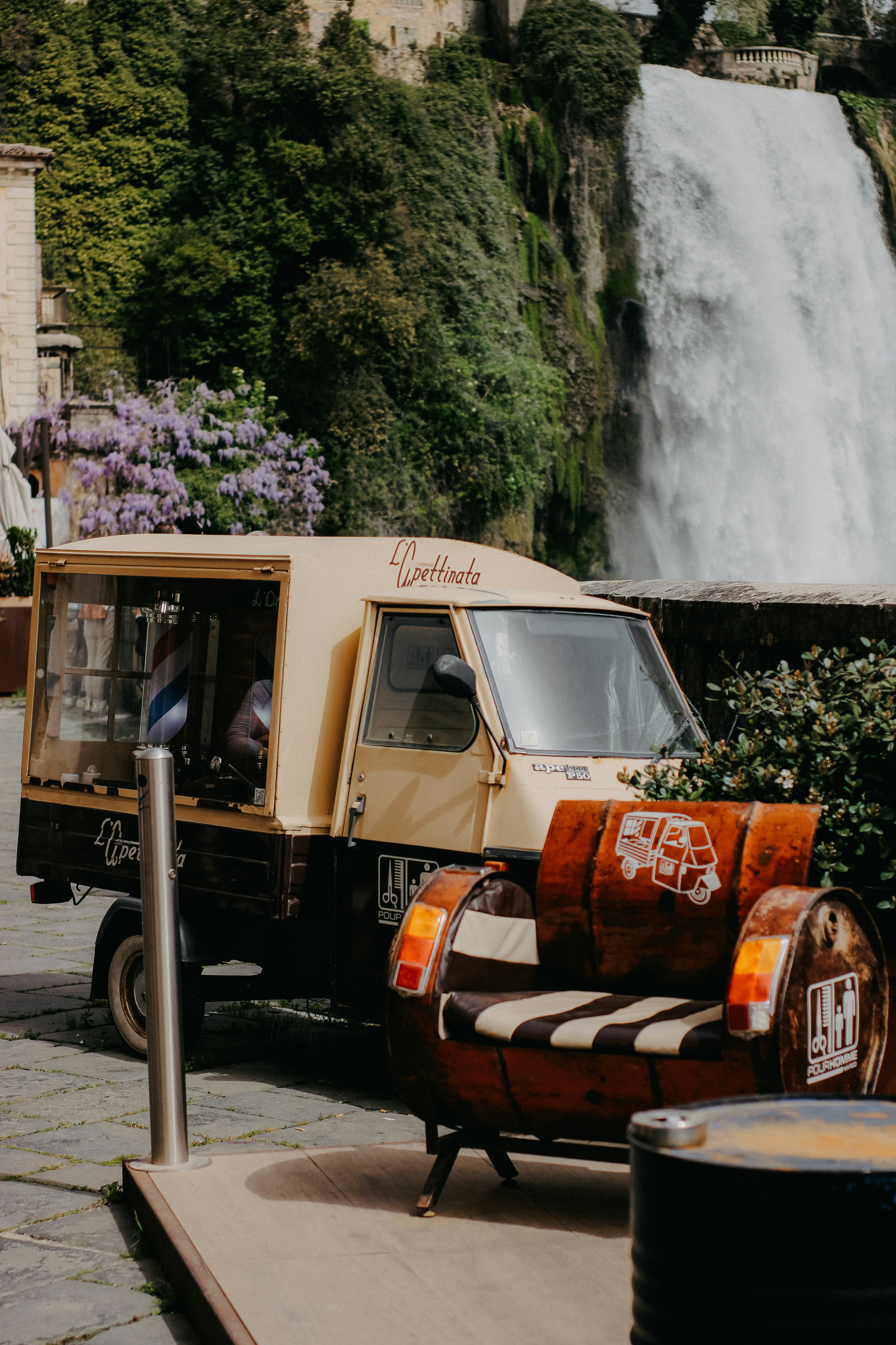 Vintage Van by the Falls: Riverside Calm Framed by Blooms and a Rusty Barrow