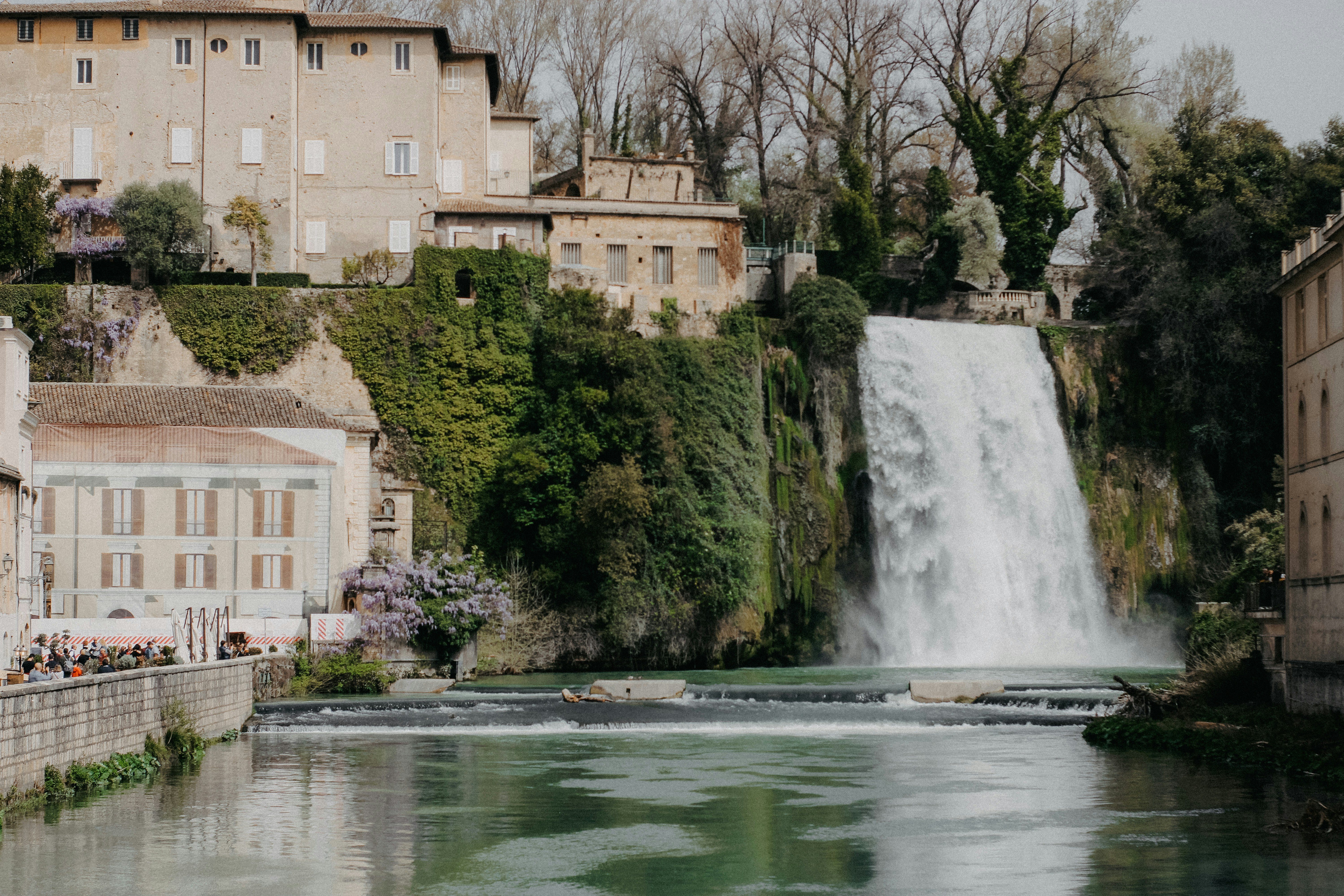 A waterfall in the middle of a river surrounded by buildings photo ...