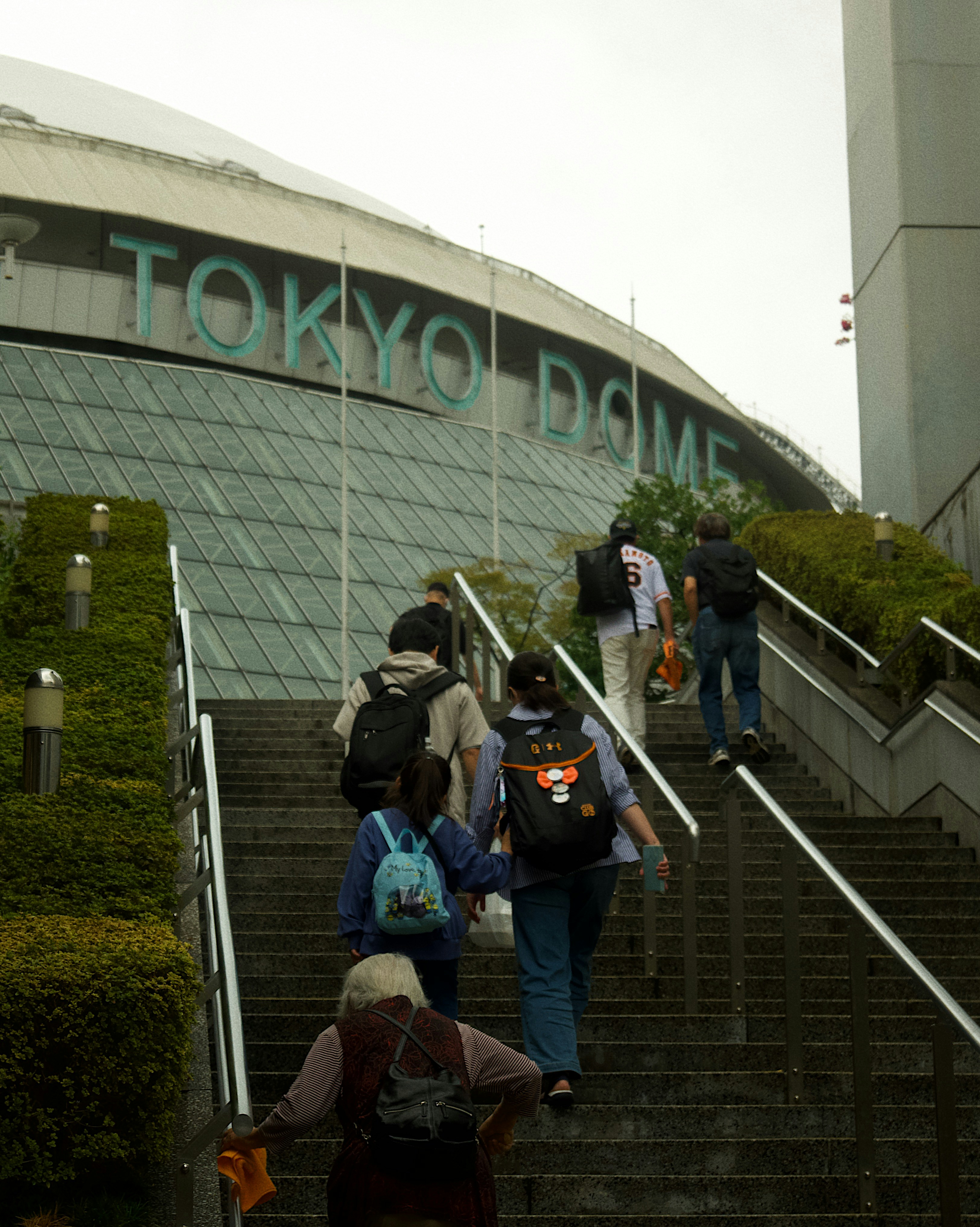 Climb to the Dome: Pedestrians ascend the glass-arched stairs toward Tokyo Dome