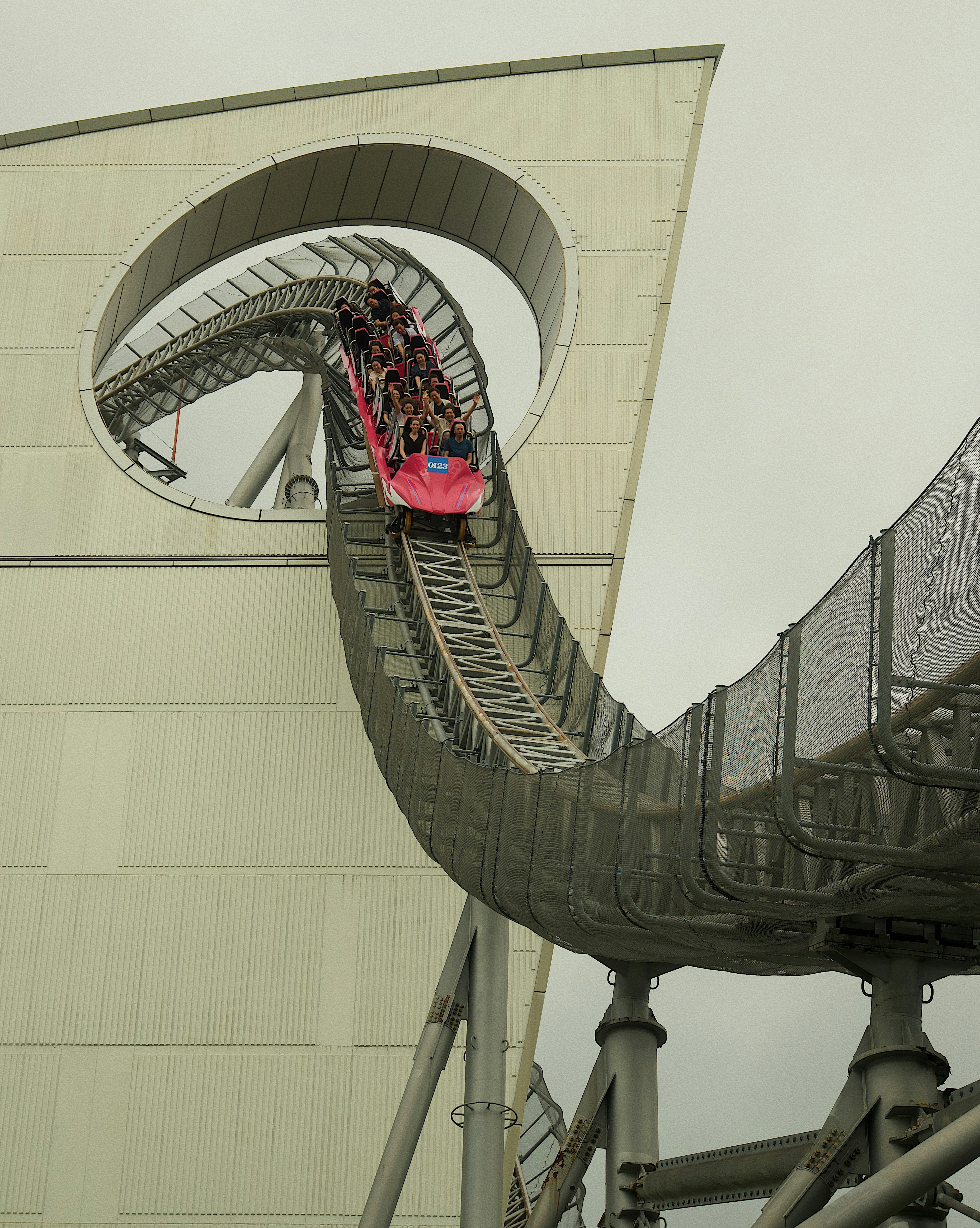 Ringed Descent: Passengers Carve a Pink Arc Through a Steel Gate