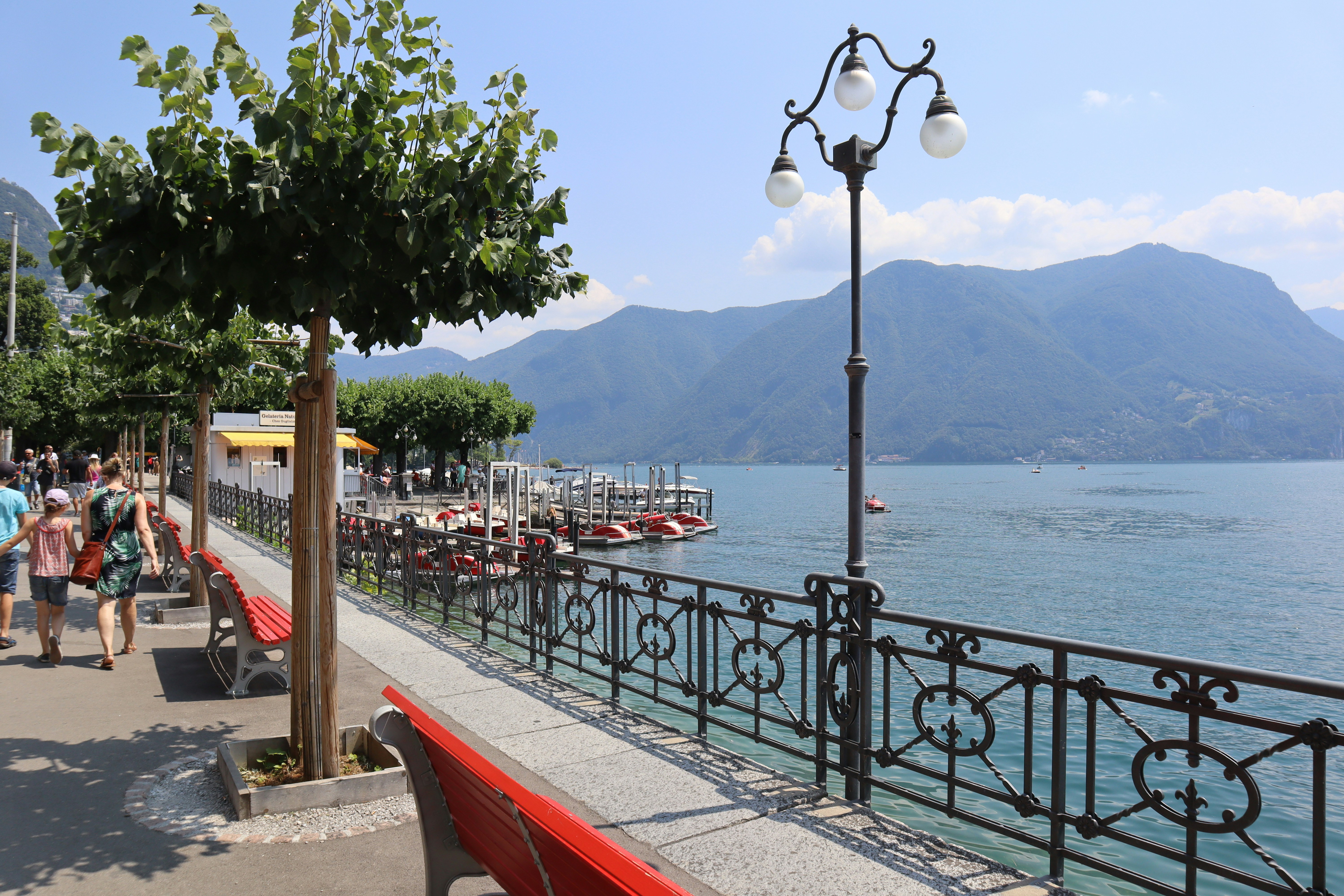 Lakeside promenade with lantern-lit railing and distant mountains