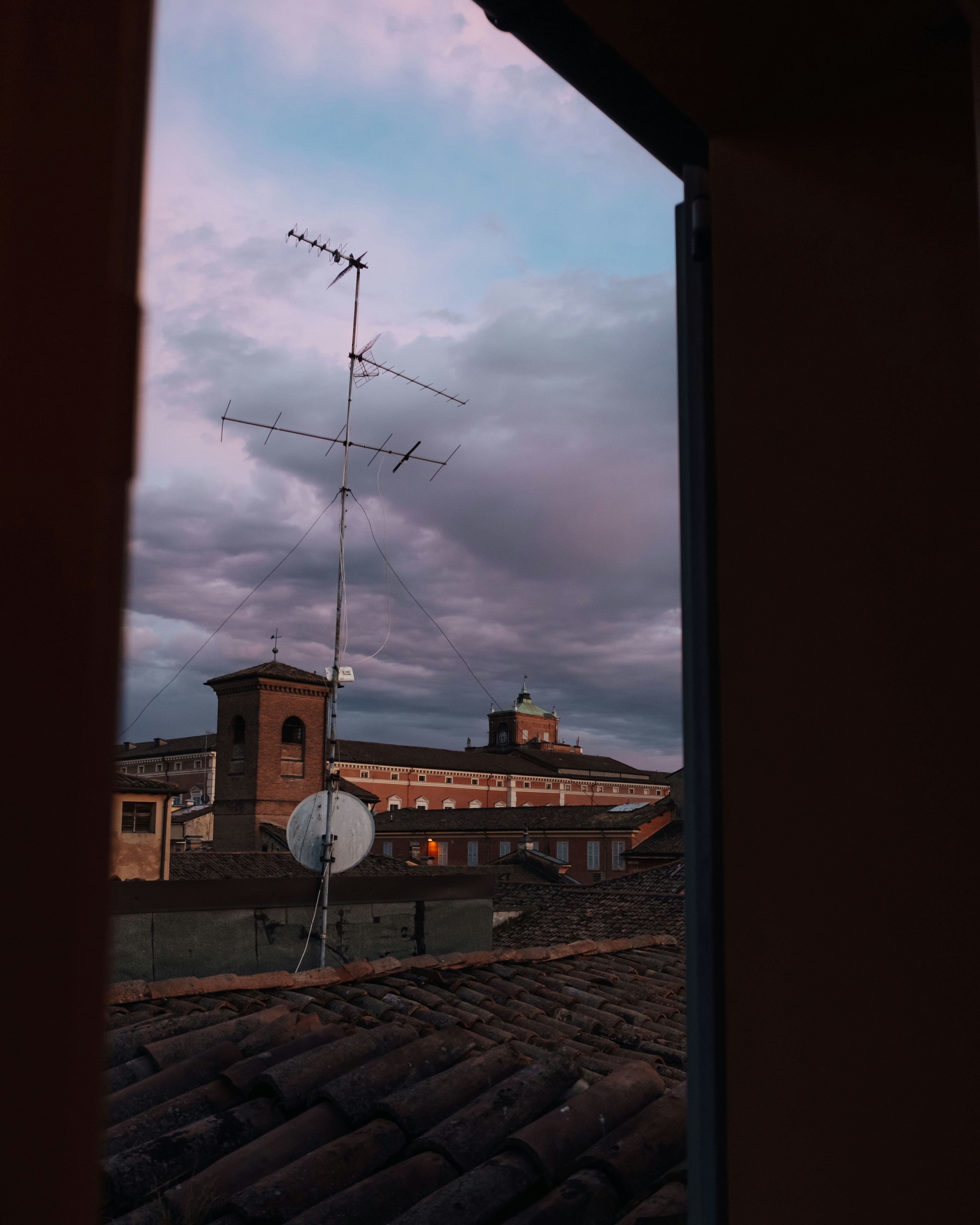 Rooftop Antenna Silhouette Seen Through a Narrow Window at Dusk