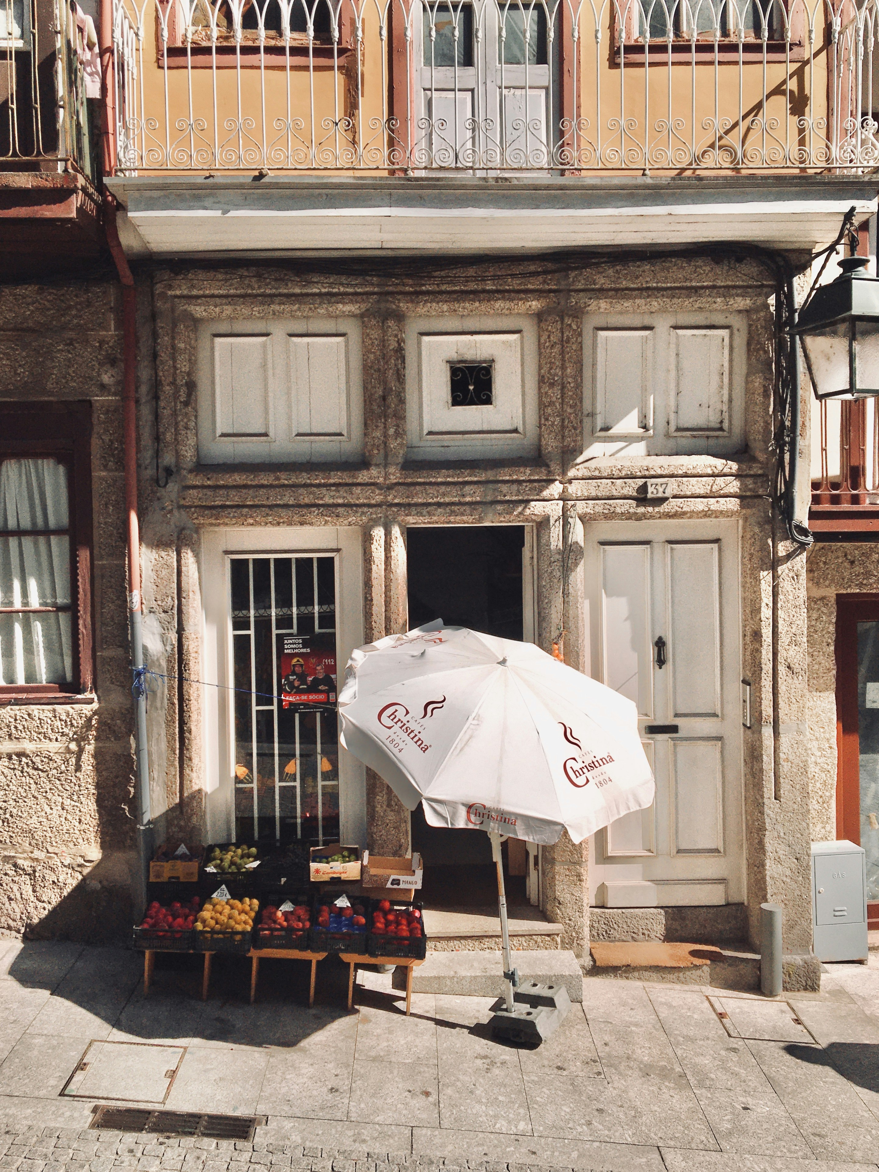 Fruit Stand under a White Umbrella Against a Weathered City Facade