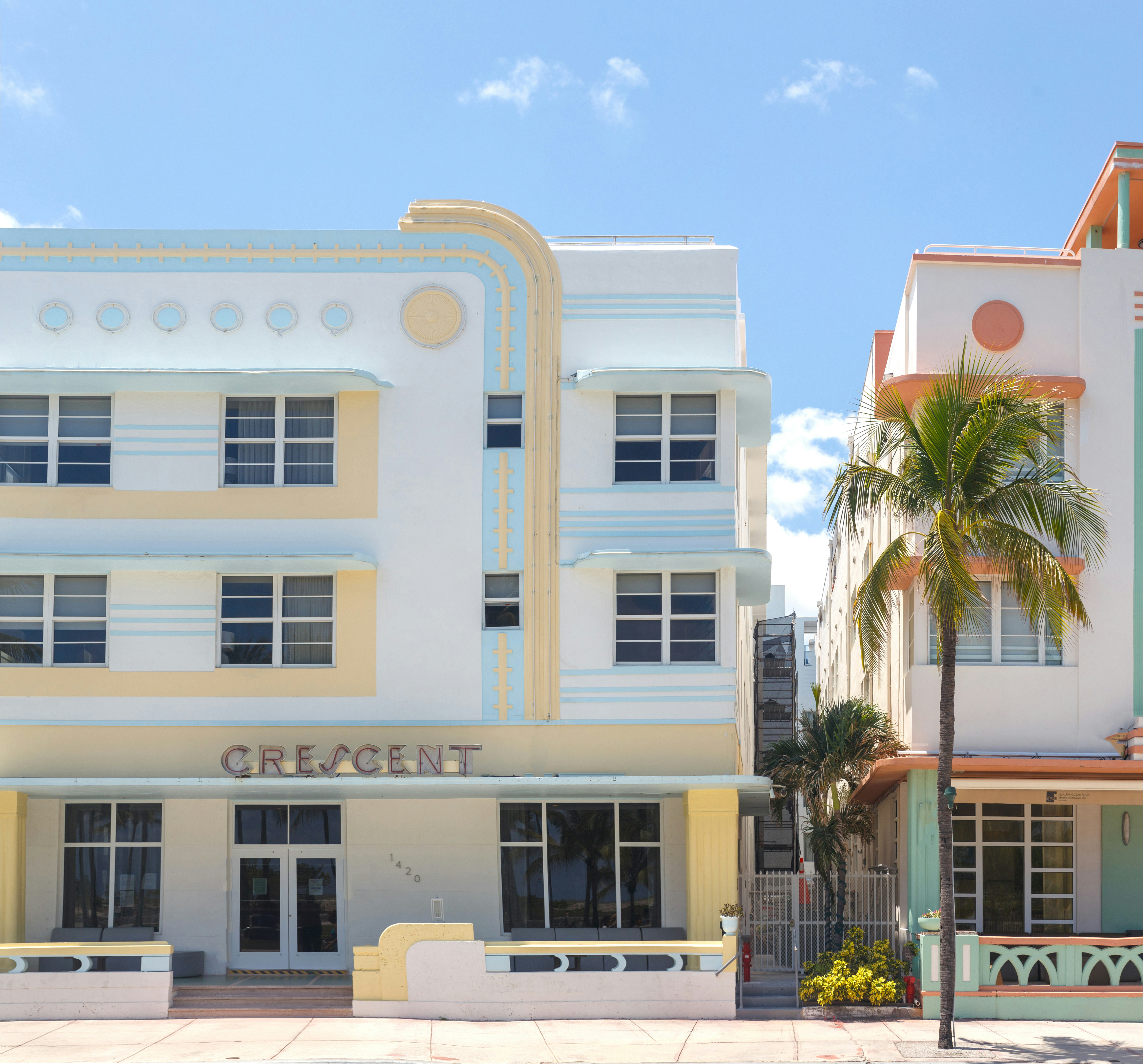 Art Deco buildings with pastel colors and geometric lines under a clear blue sky.