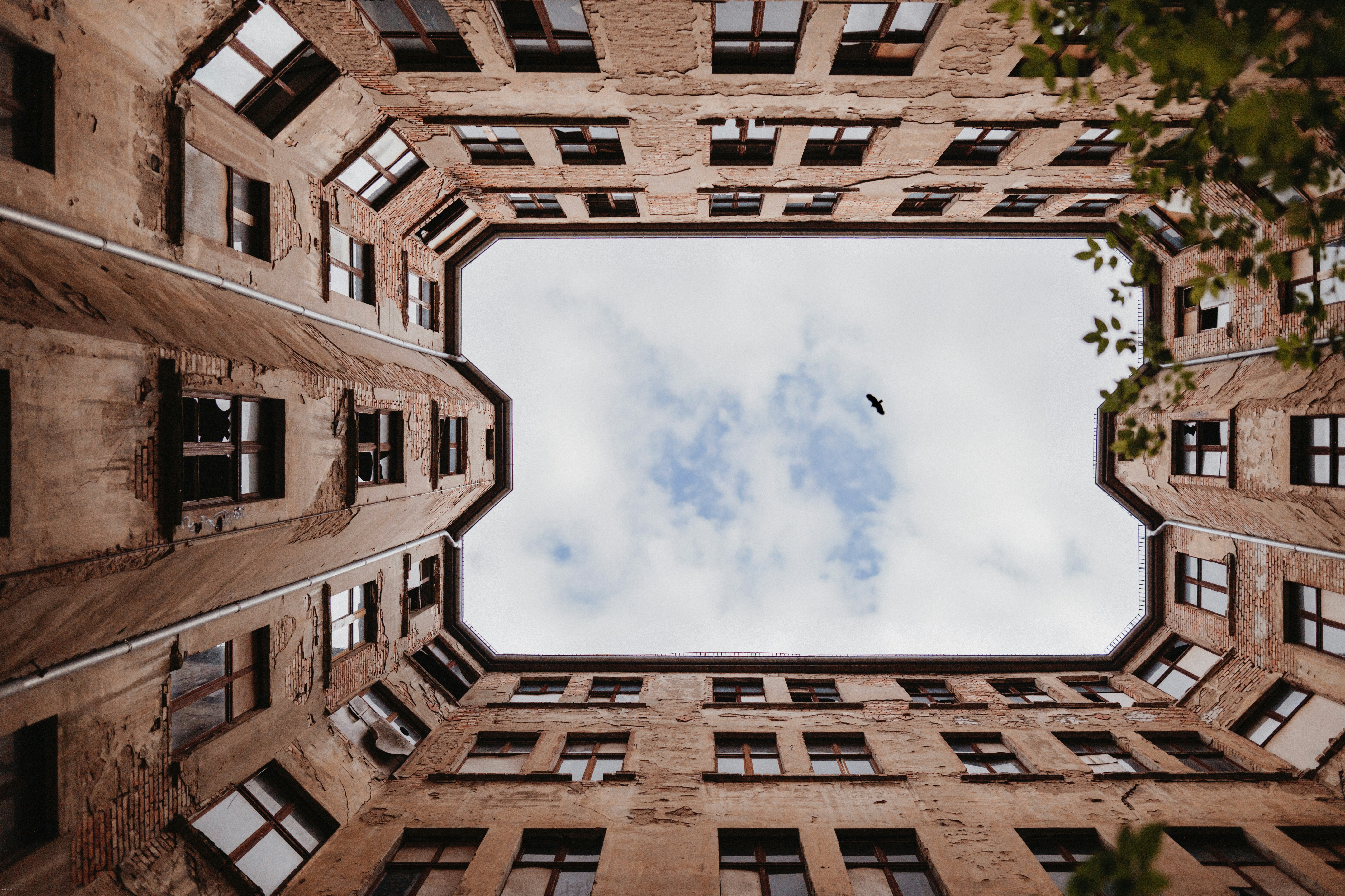 Looking up at a rectangular courtyard framed by tall brick buildings with a patch of sky overhead.