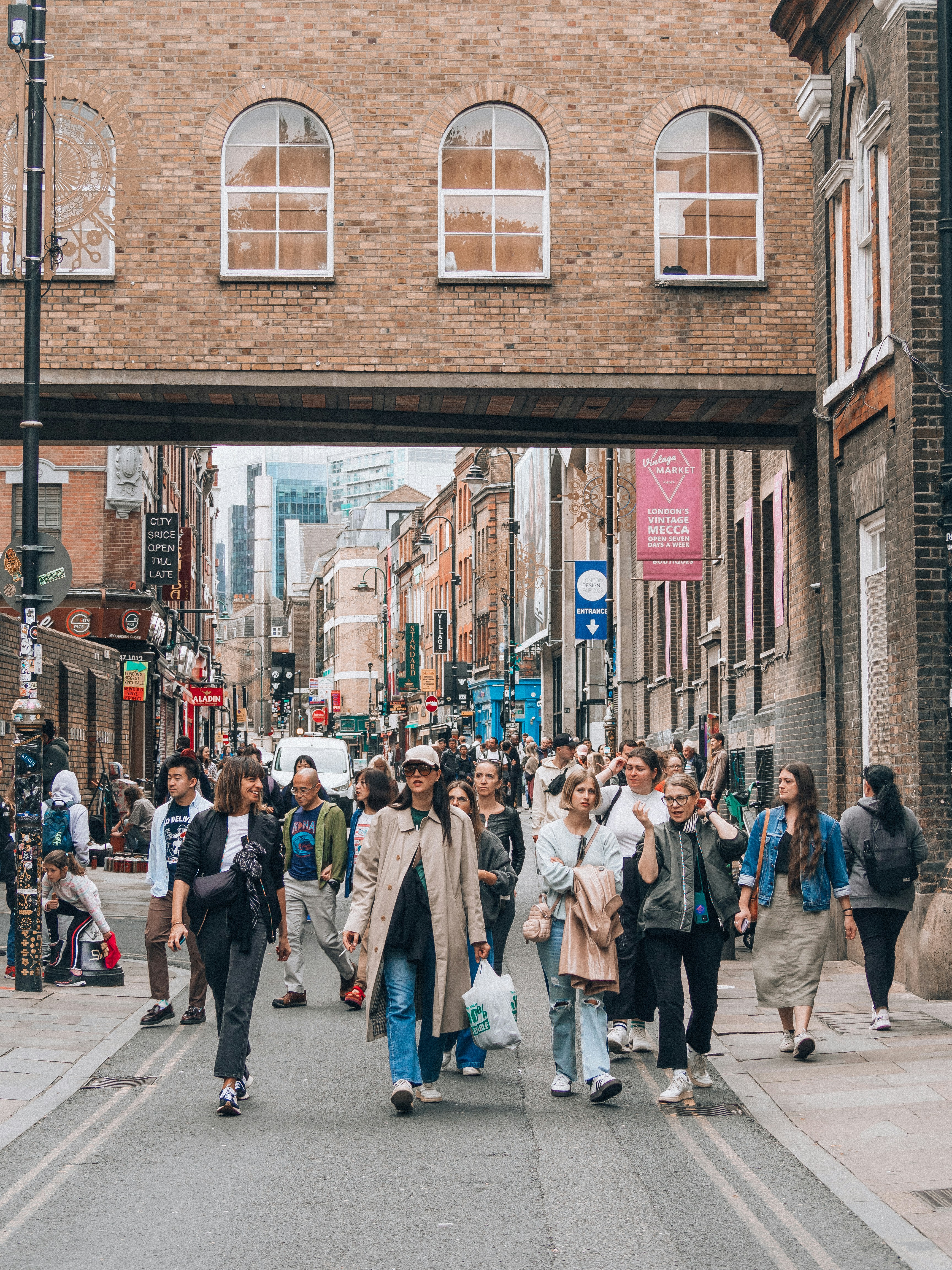 Bustling street scene with diverse pedestrians navigating a lively urban environment, framed by historic architecture and modern buildings.
