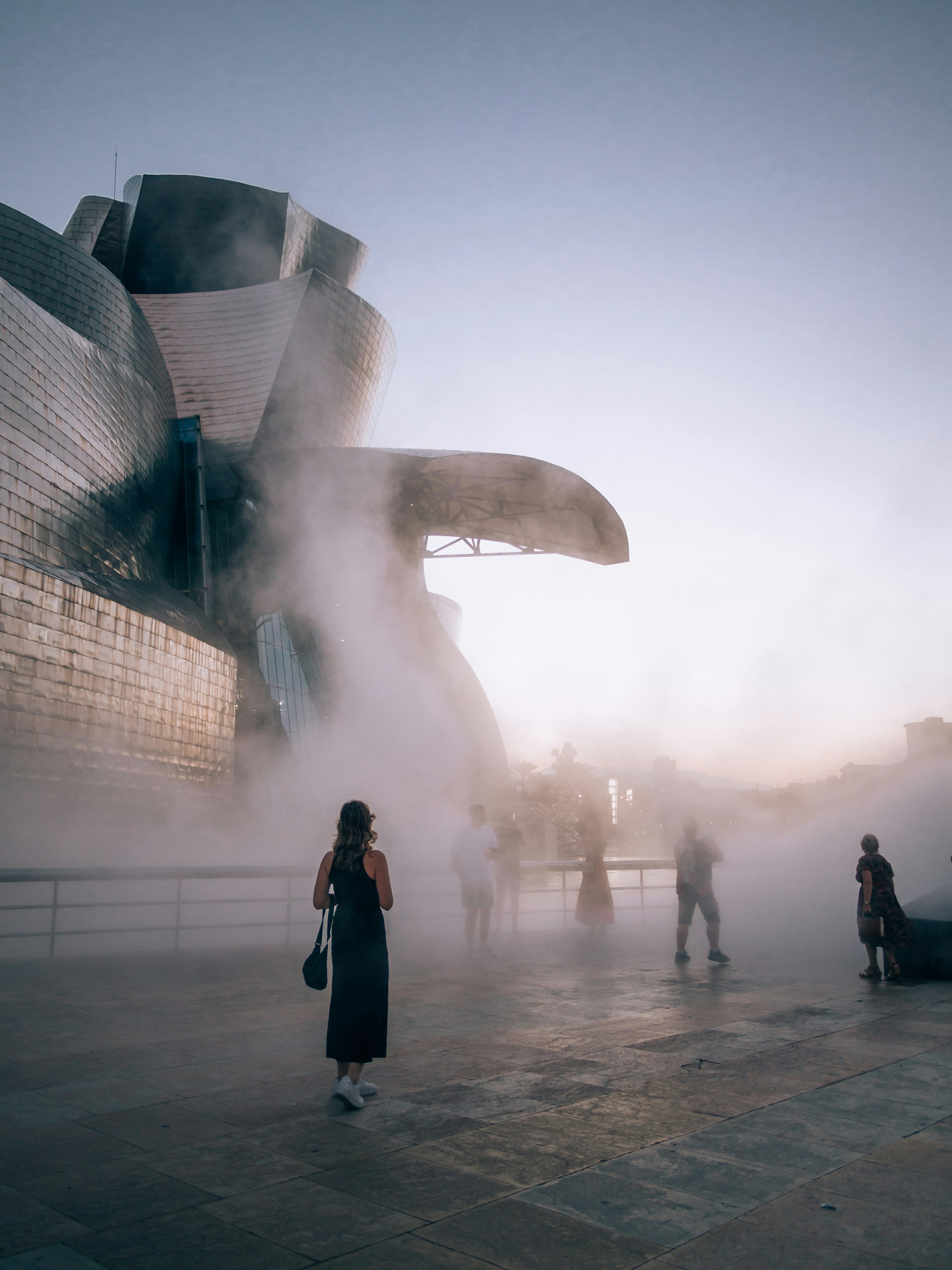 Steam on Titanium: A Figure in Quiet Contrast Against a Morphing Facade