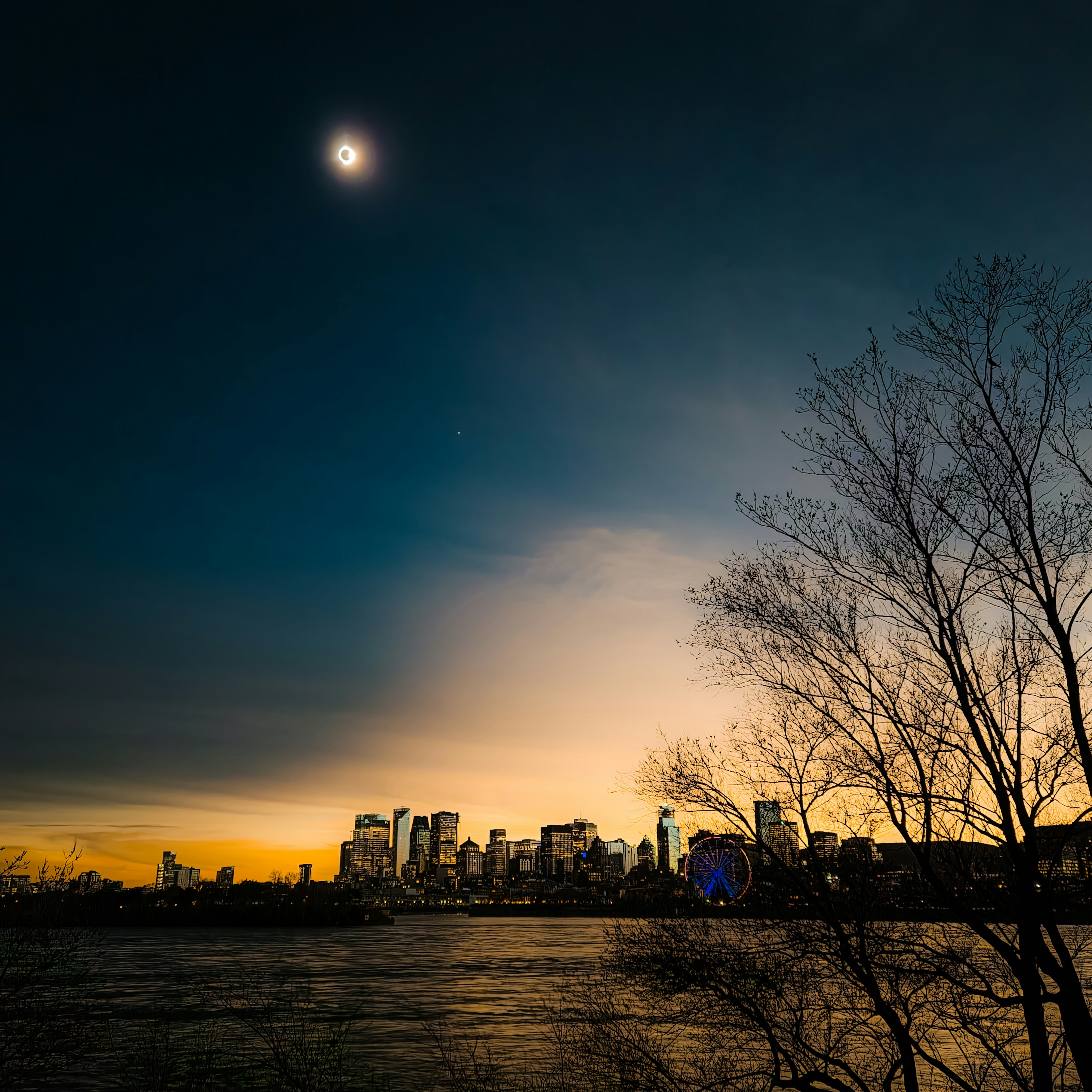 Blue Ring Adorns the Riverside Cityscape at Dusk