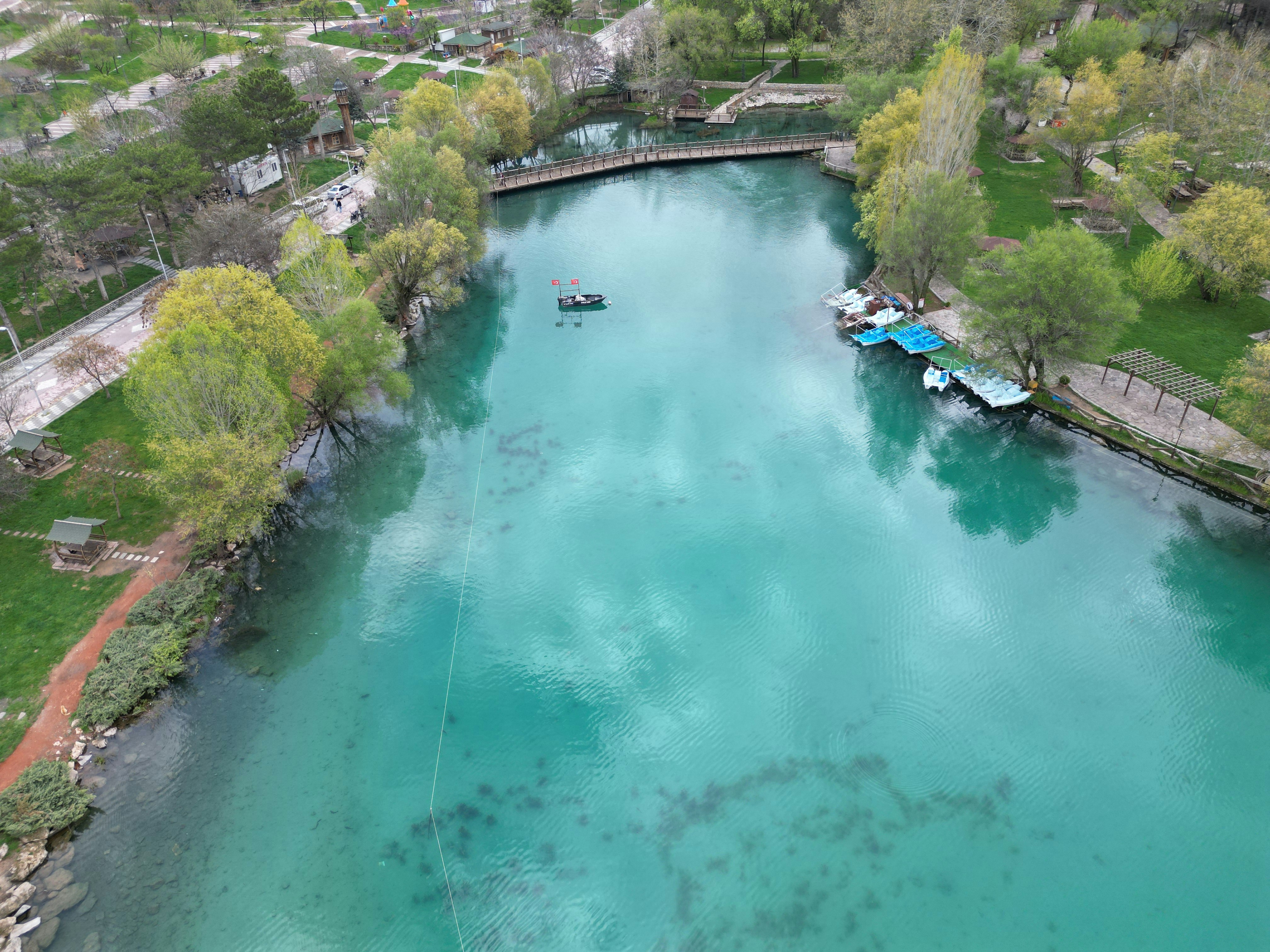 Teal Tranquility: Lone Boat on a Tree-Lined Park River