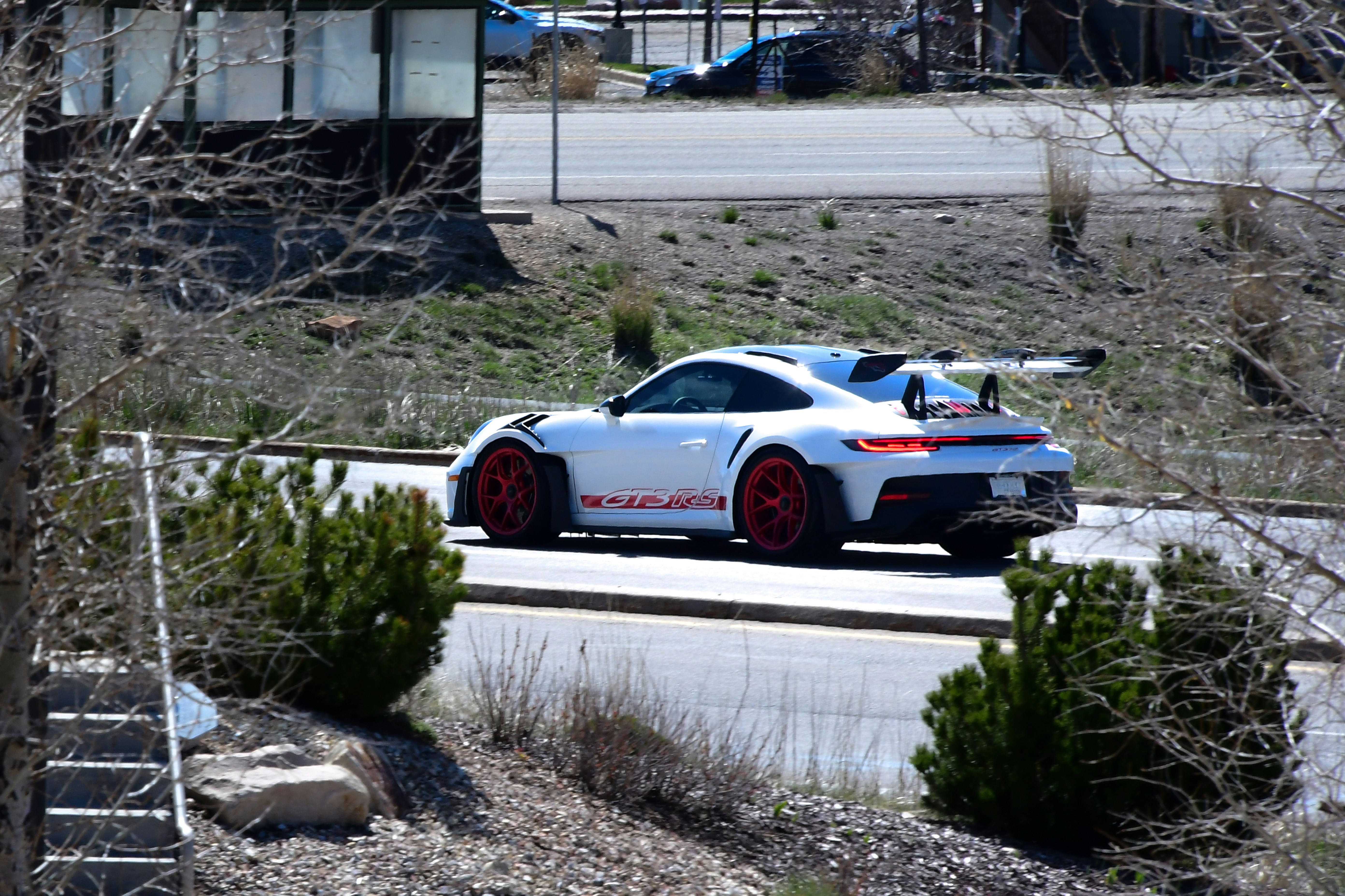 White Porsche GT3 on a desert road, red-rimmed wheels slicing through scrub