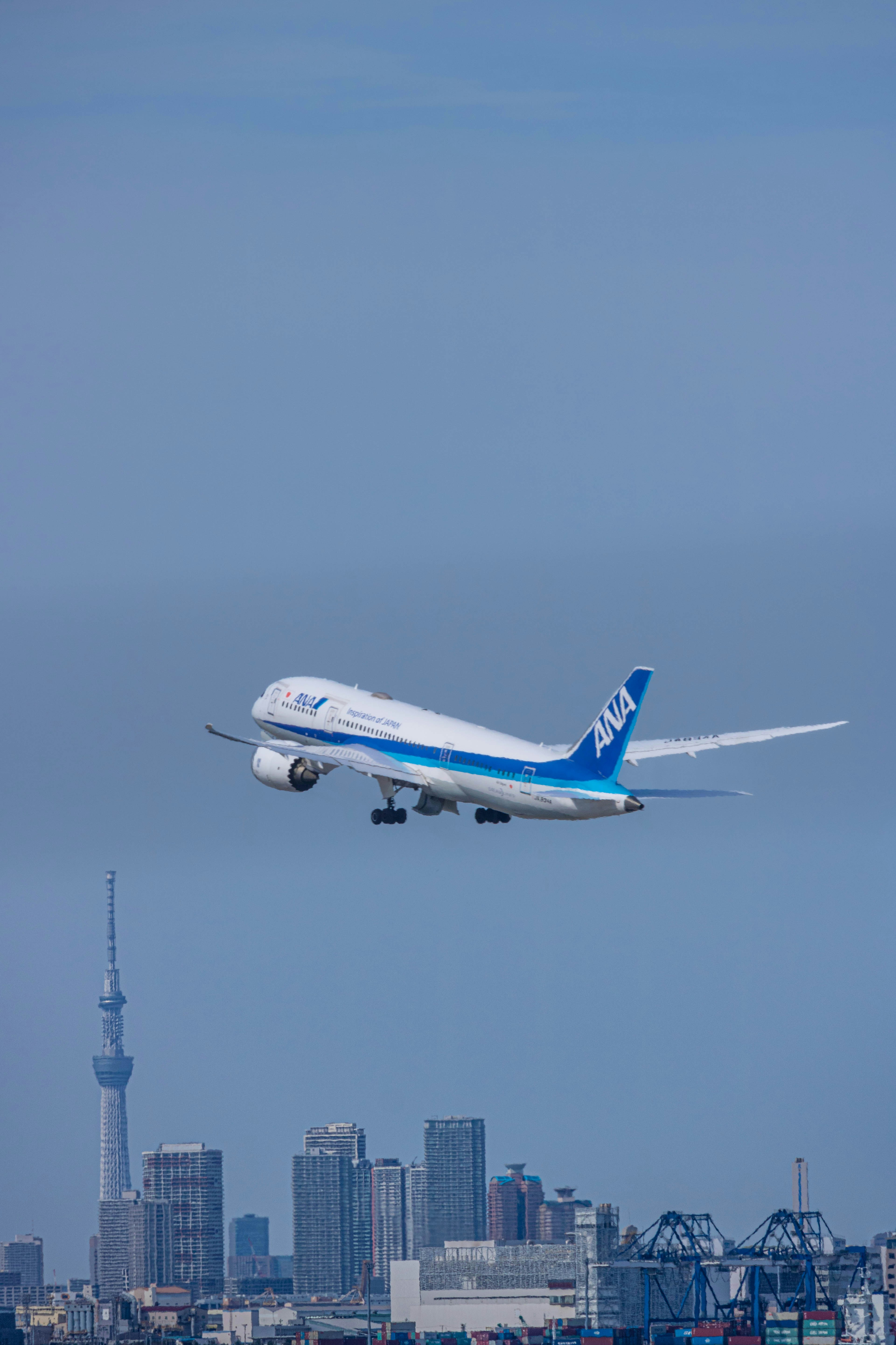 A large passenger jet flying over a city photo – Free Haneda airport ...