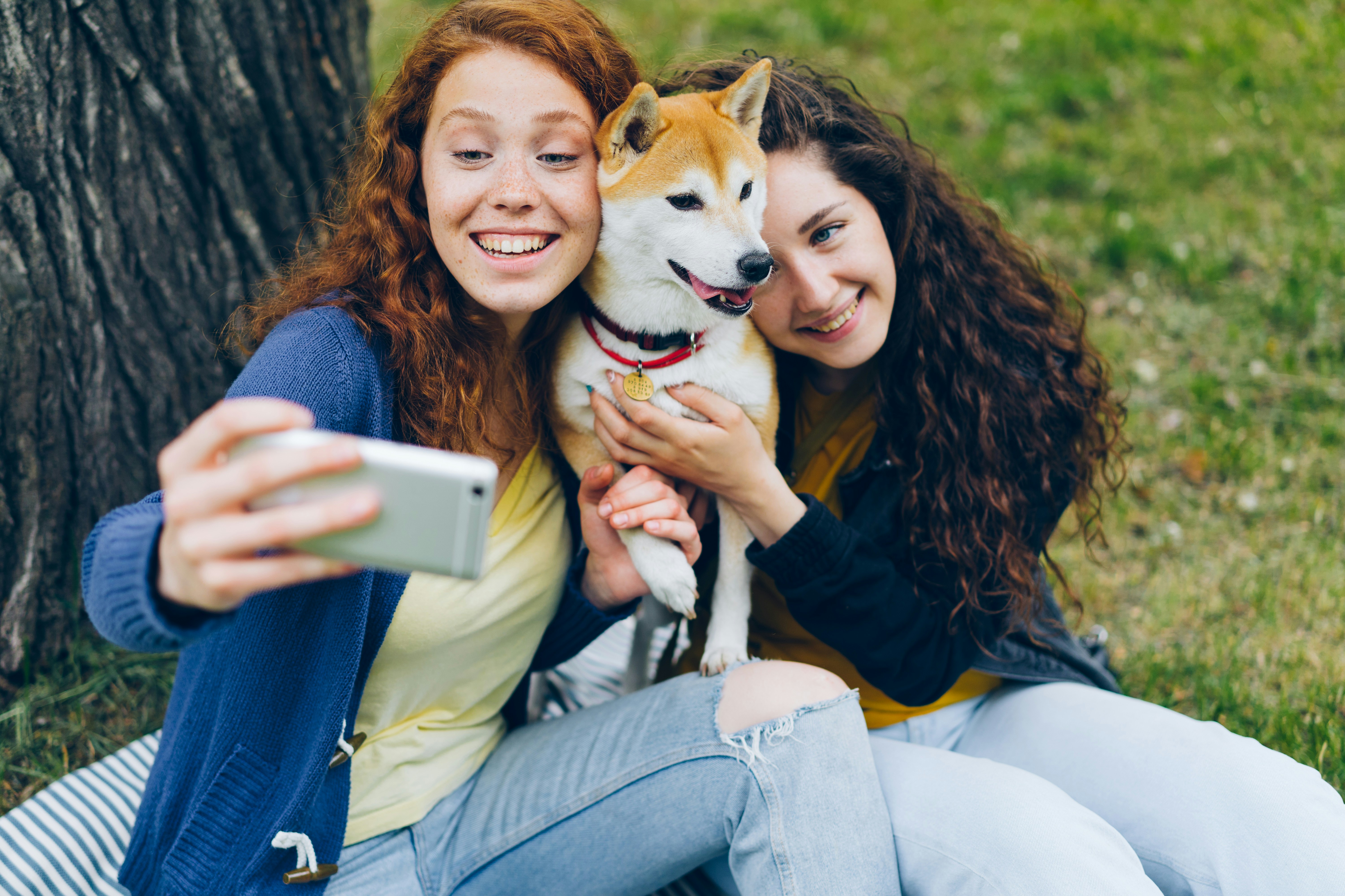 Two women sitting next to each other holding a dog photo – Free Image ...
