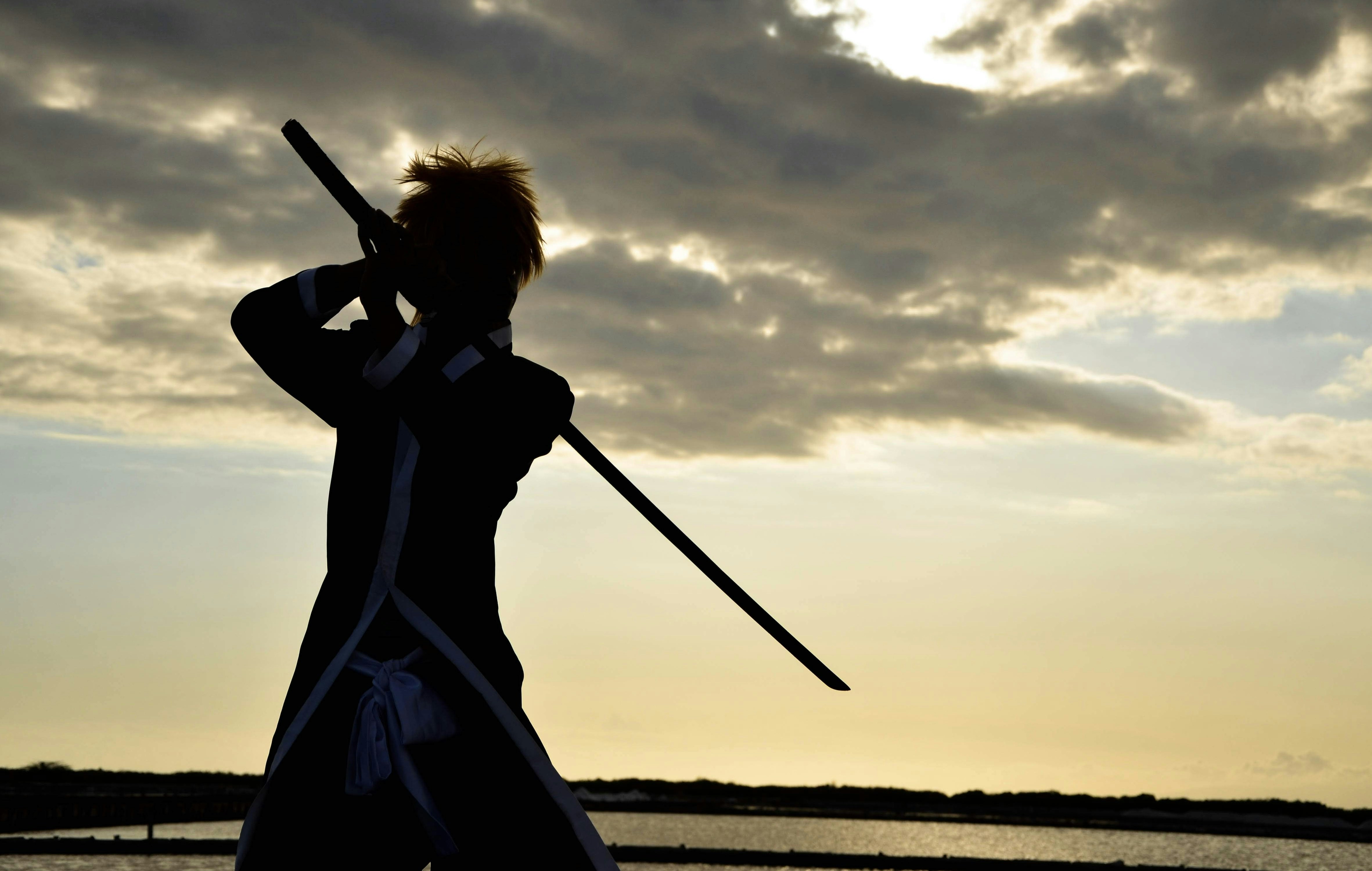 A person with a sword standing in front of a body of water photo – Free ...