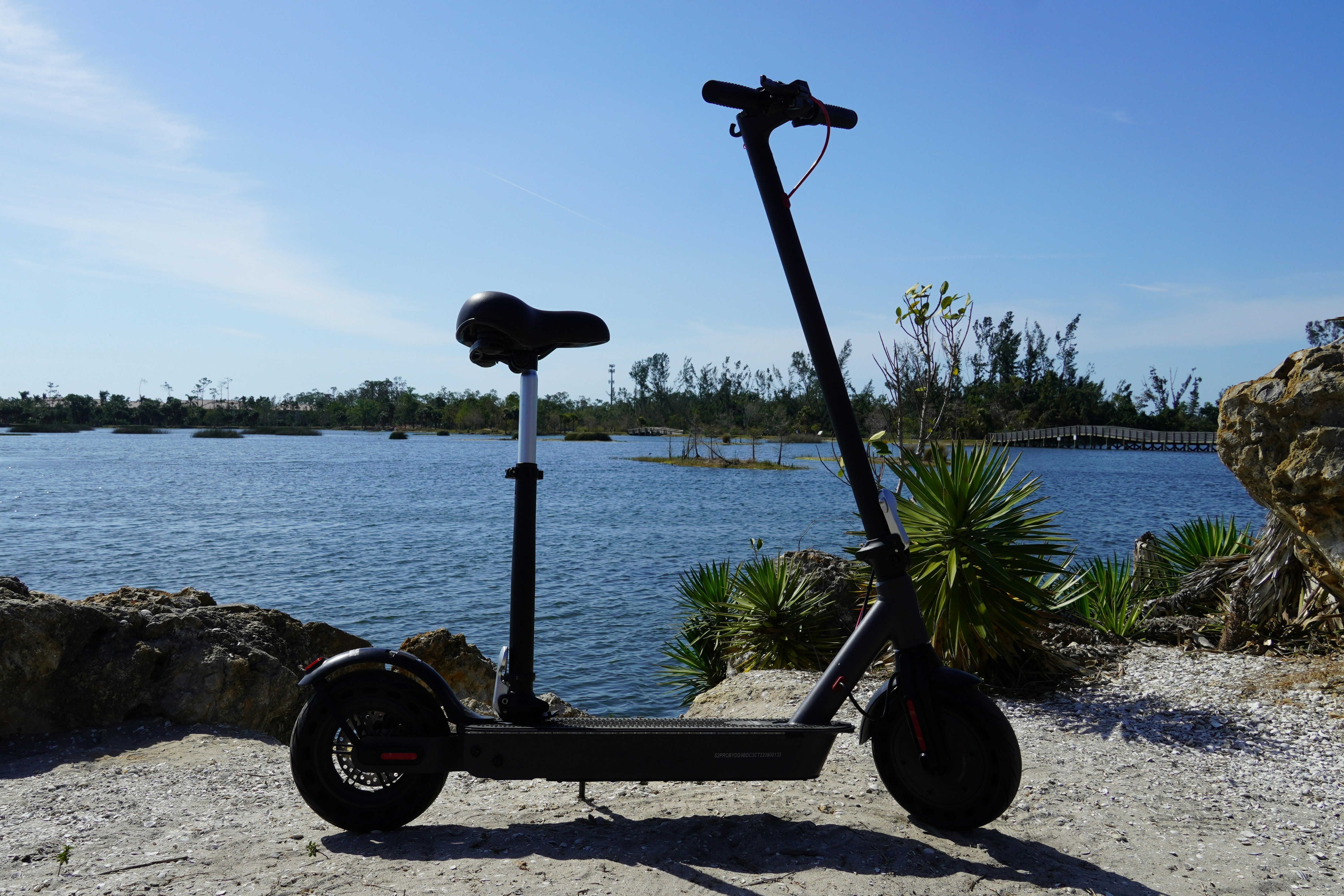 A scooter parked on a beach next to a body of water photo – Free ...
