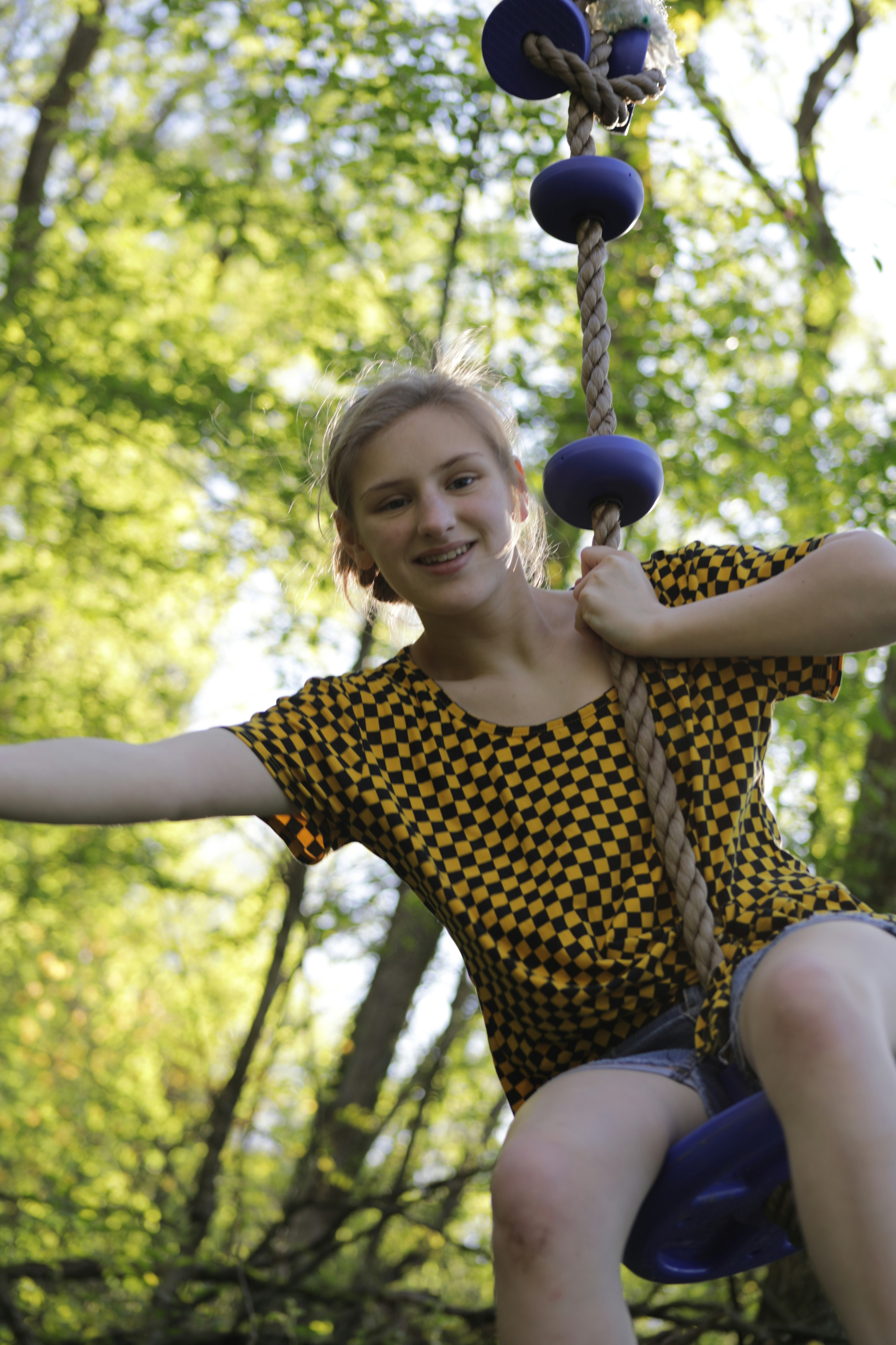 Youthful swing: a girl on a rope ride framed against sunlit trees