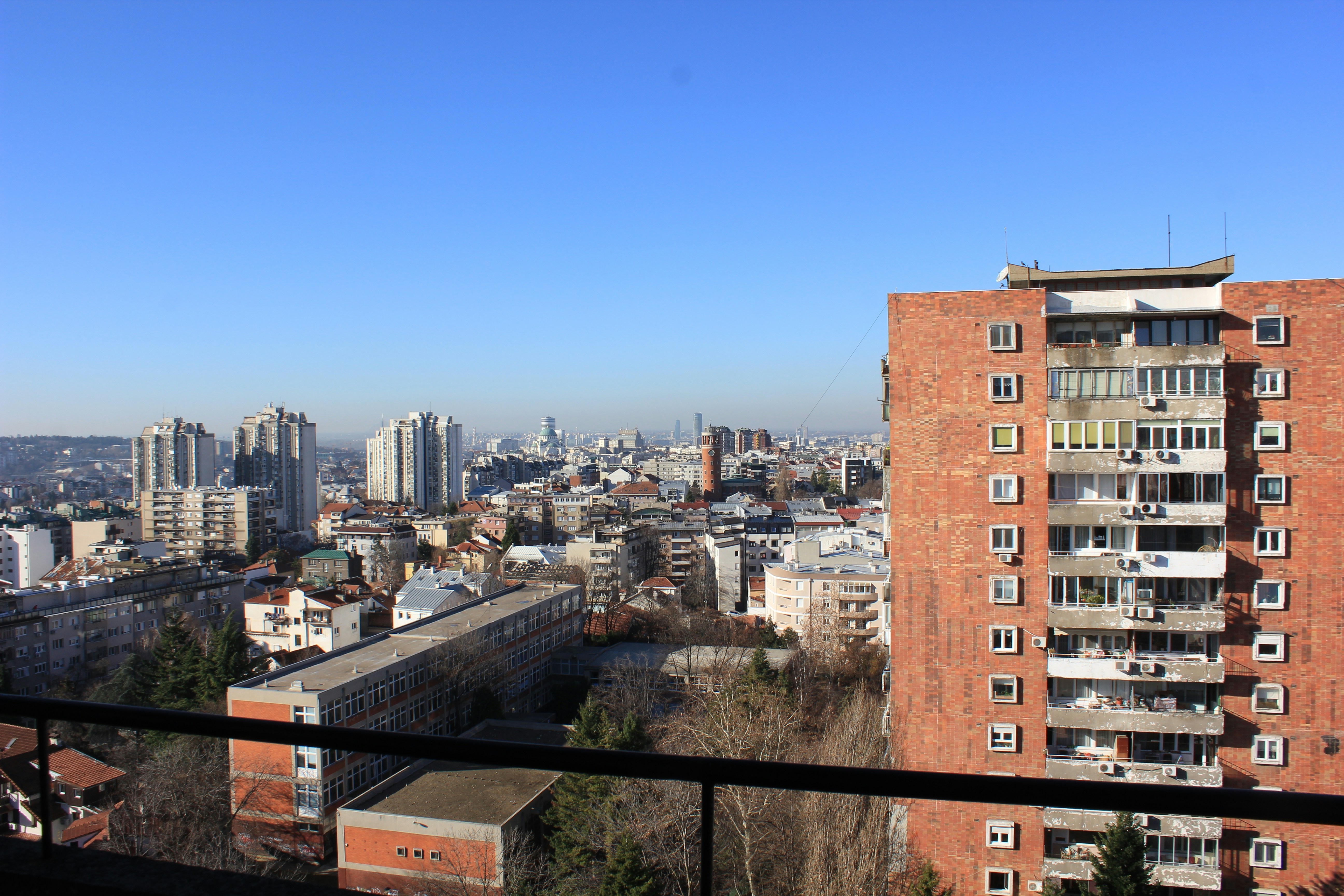 Panoramic view of a vibrant urban landscape featuring residential buildings and city skyline under a clear blue sky.