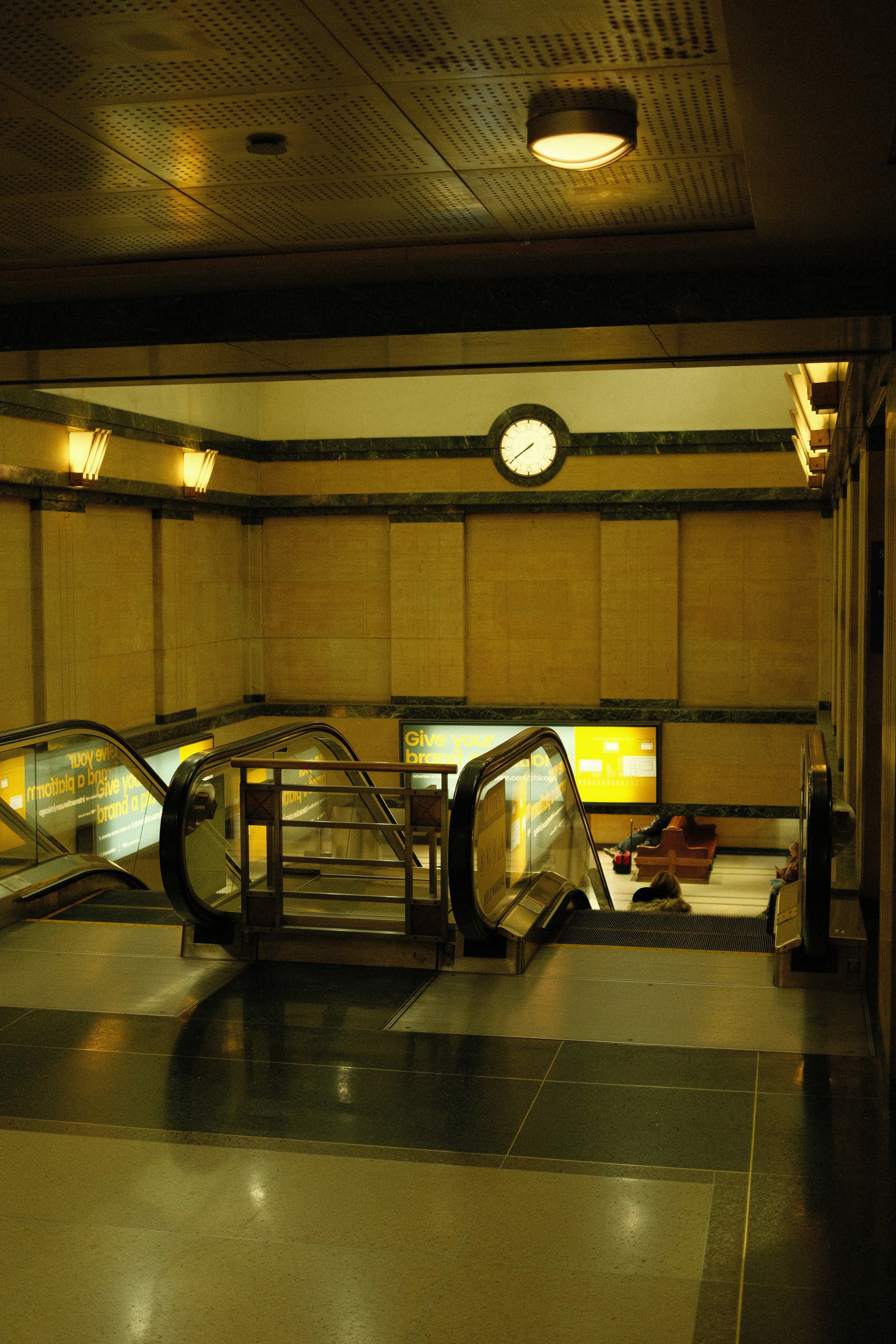 Clocklit Descent: Escalators and Warm Ambience in a Subterranean Hall