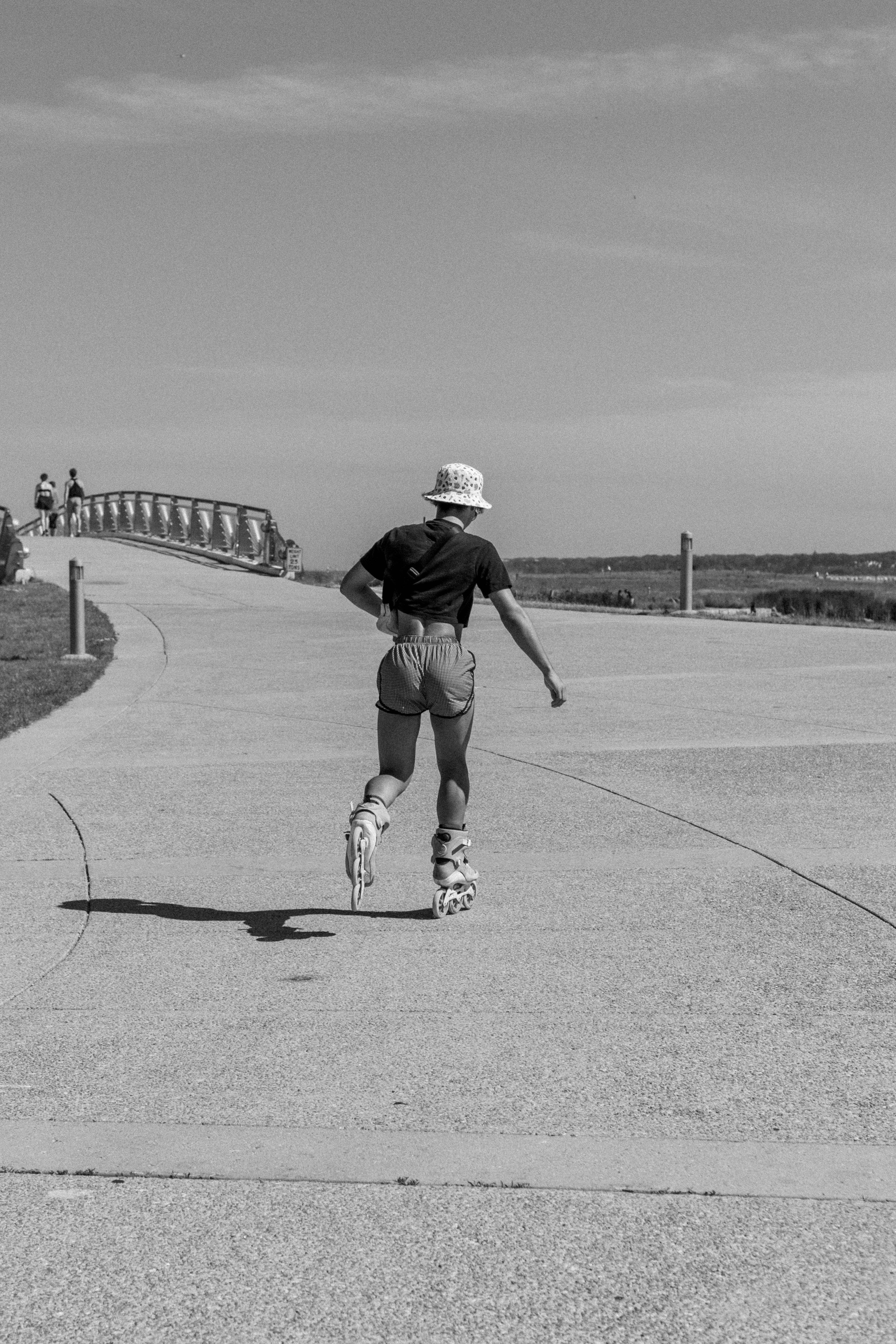 Curved Waterfront Glide: A Solo Rollerblader on a Sunlit Promenade