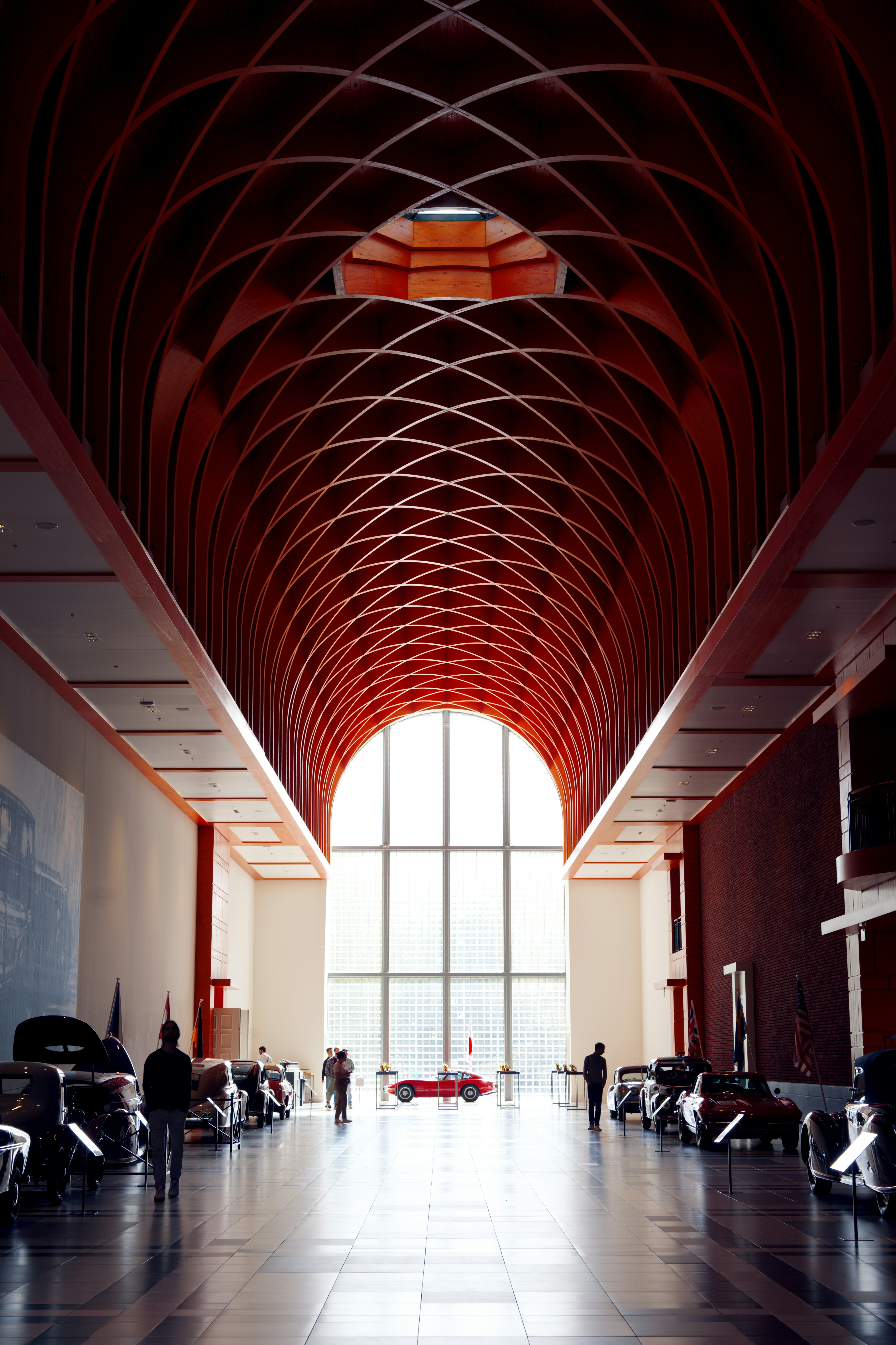 Crimson Arches Converge on a Red Car at the Showroom's End