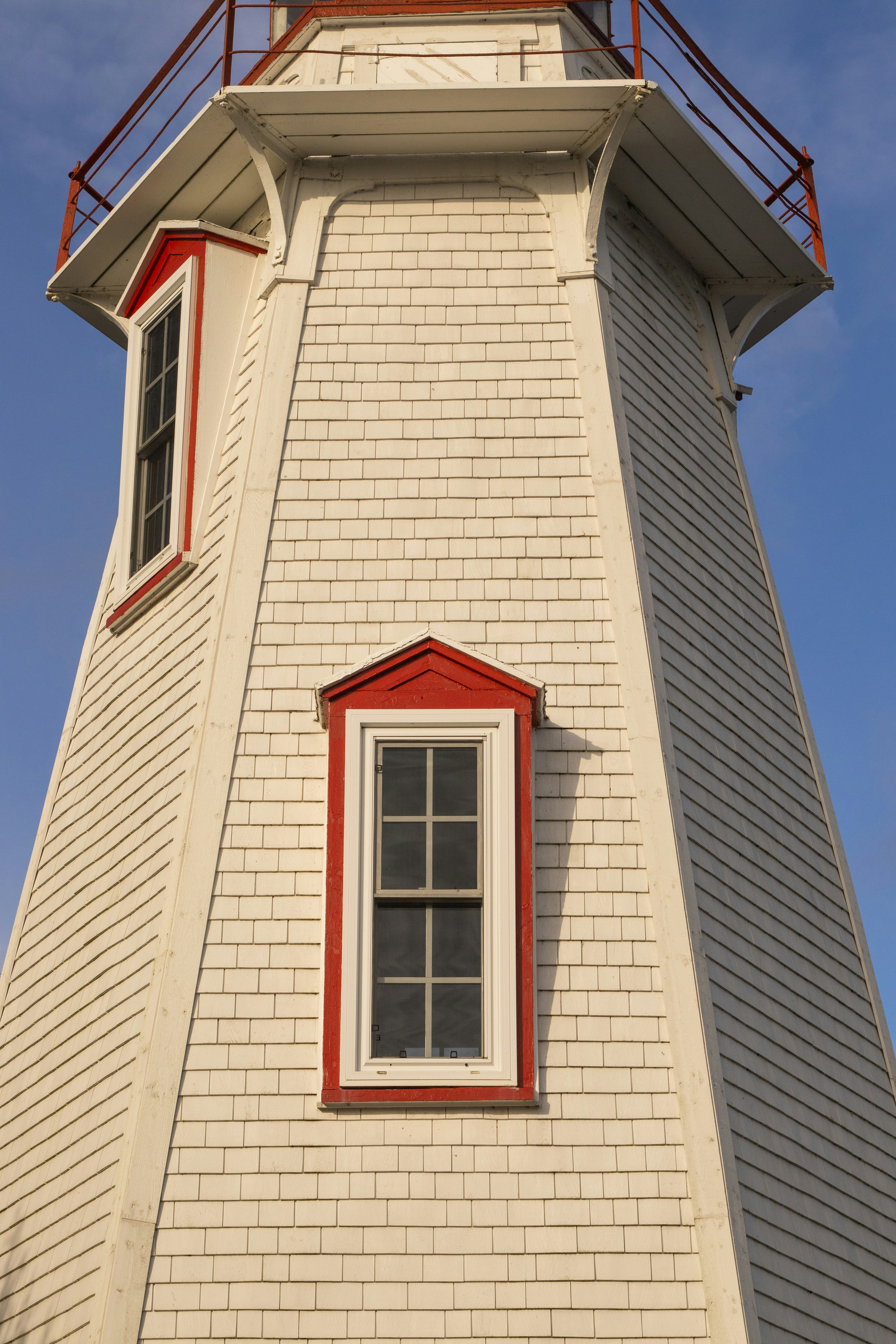 Crimson-Framed Beacon: A White Lighthouse Rising Against a Pristine Blue Sky