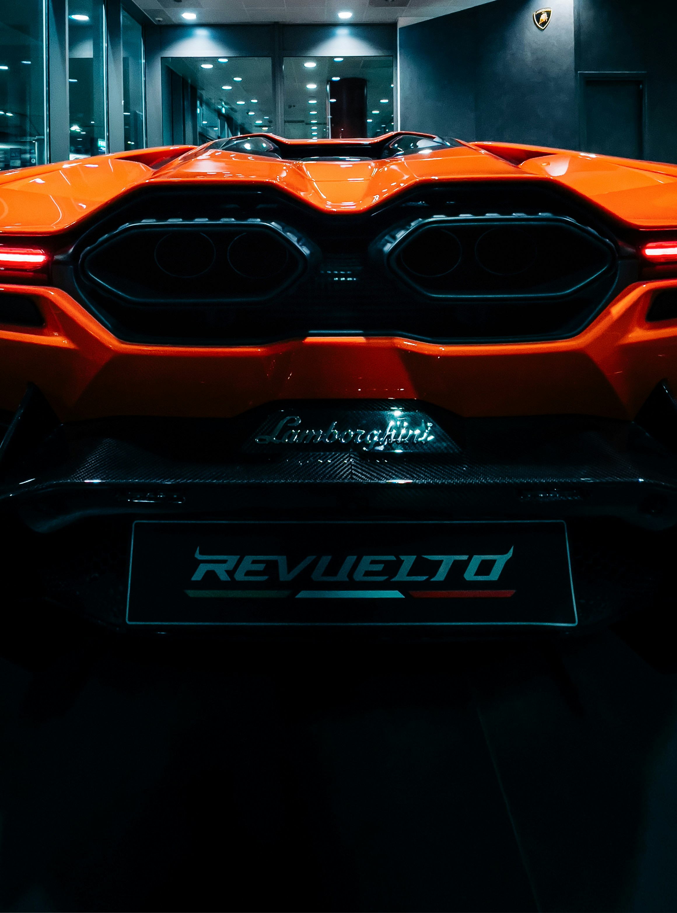 Revuelto Rearview: Sculpted Orange Power Under Neon Showroom Lights
