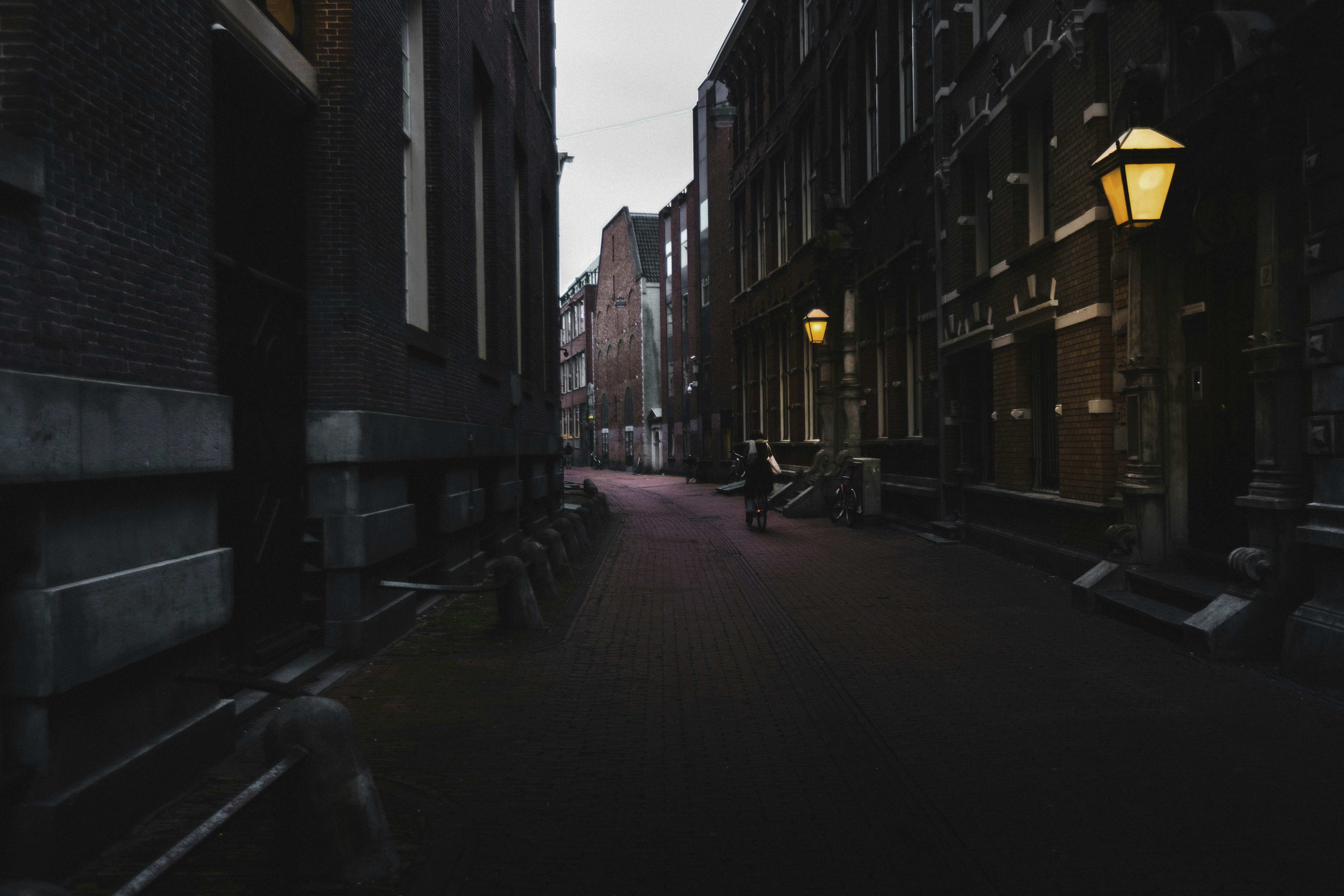 A person riding a bike down a dark street photo – Free Alley Image on ...