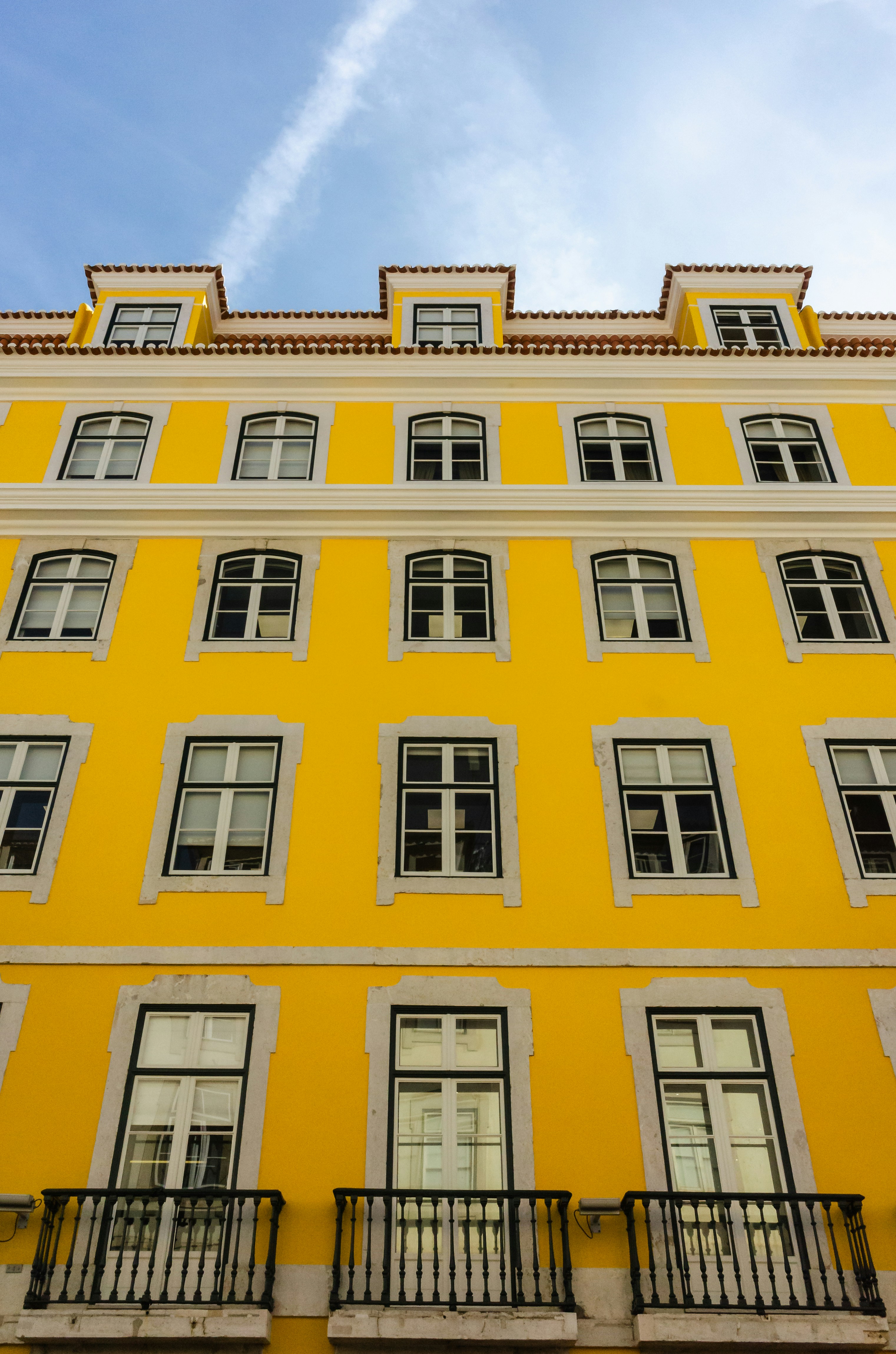 A tall yellow building with many windows and balconies photo – Free ...