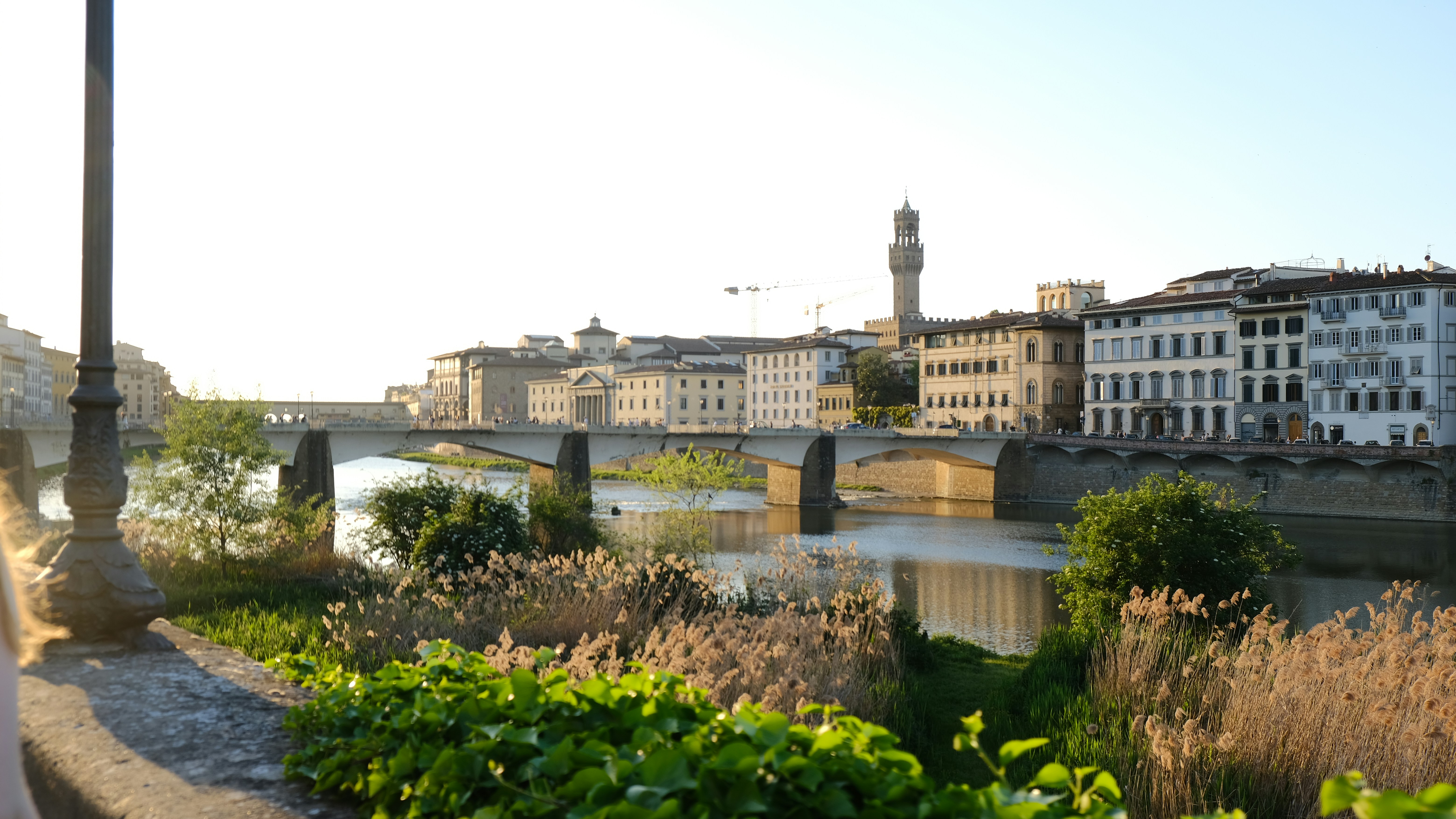 Evening Over the Arno: Arched Bridge, Shimmering Water, and a Timeless Clocktower
