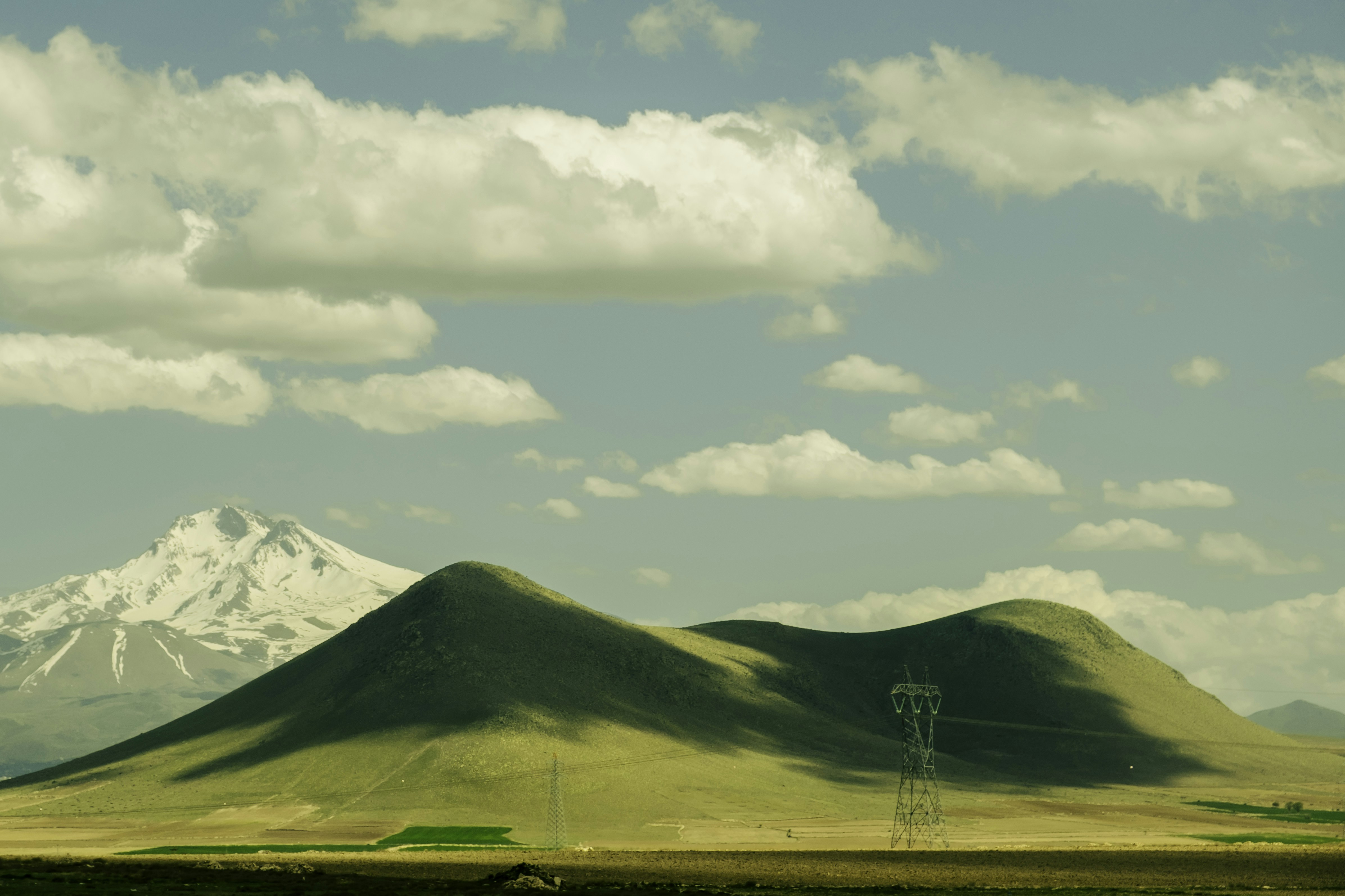 Emerald Mounds Under a Snow-Kissed Sentinel