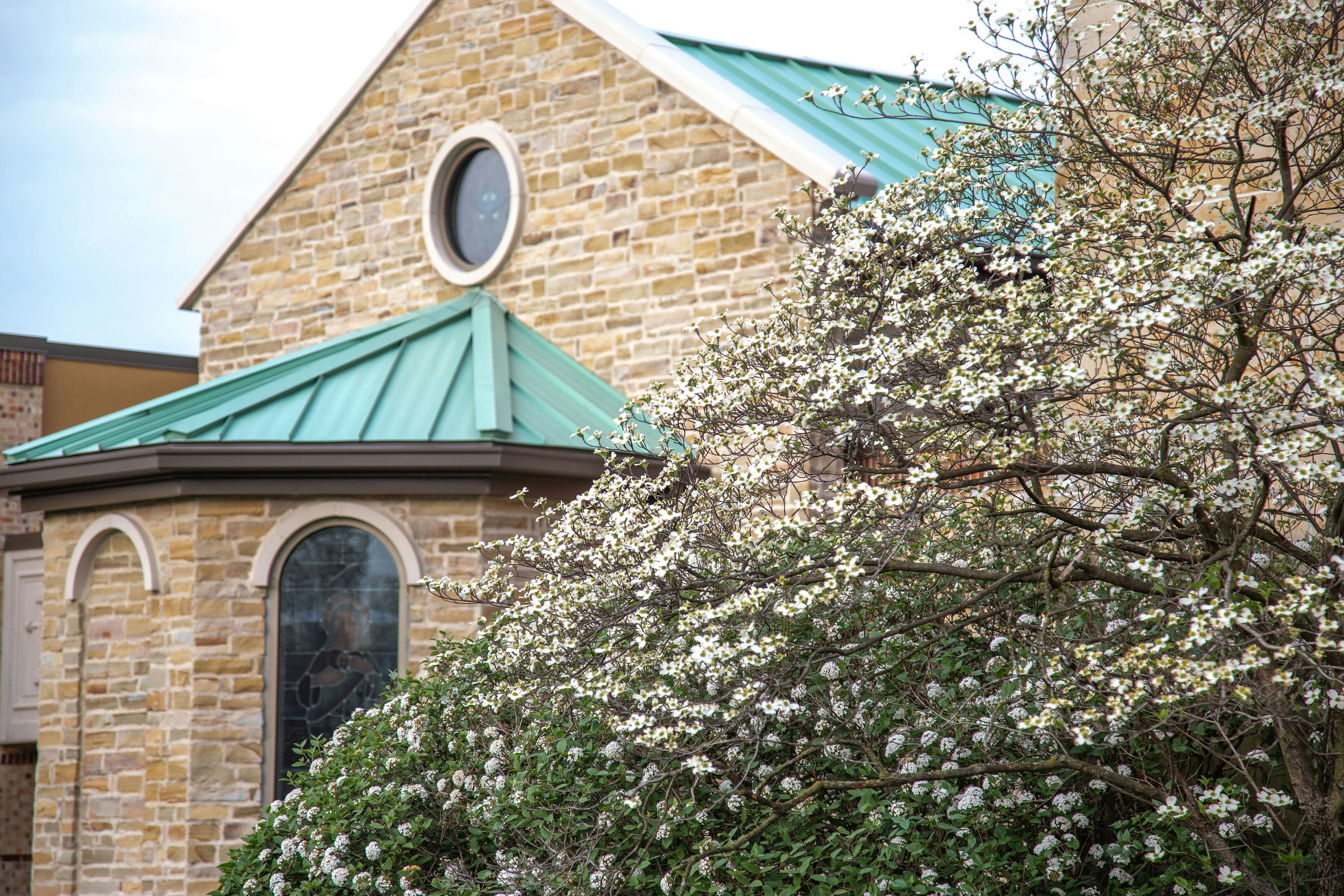 Teal-Roofed Stone Chapel Framed by Spring Blooms