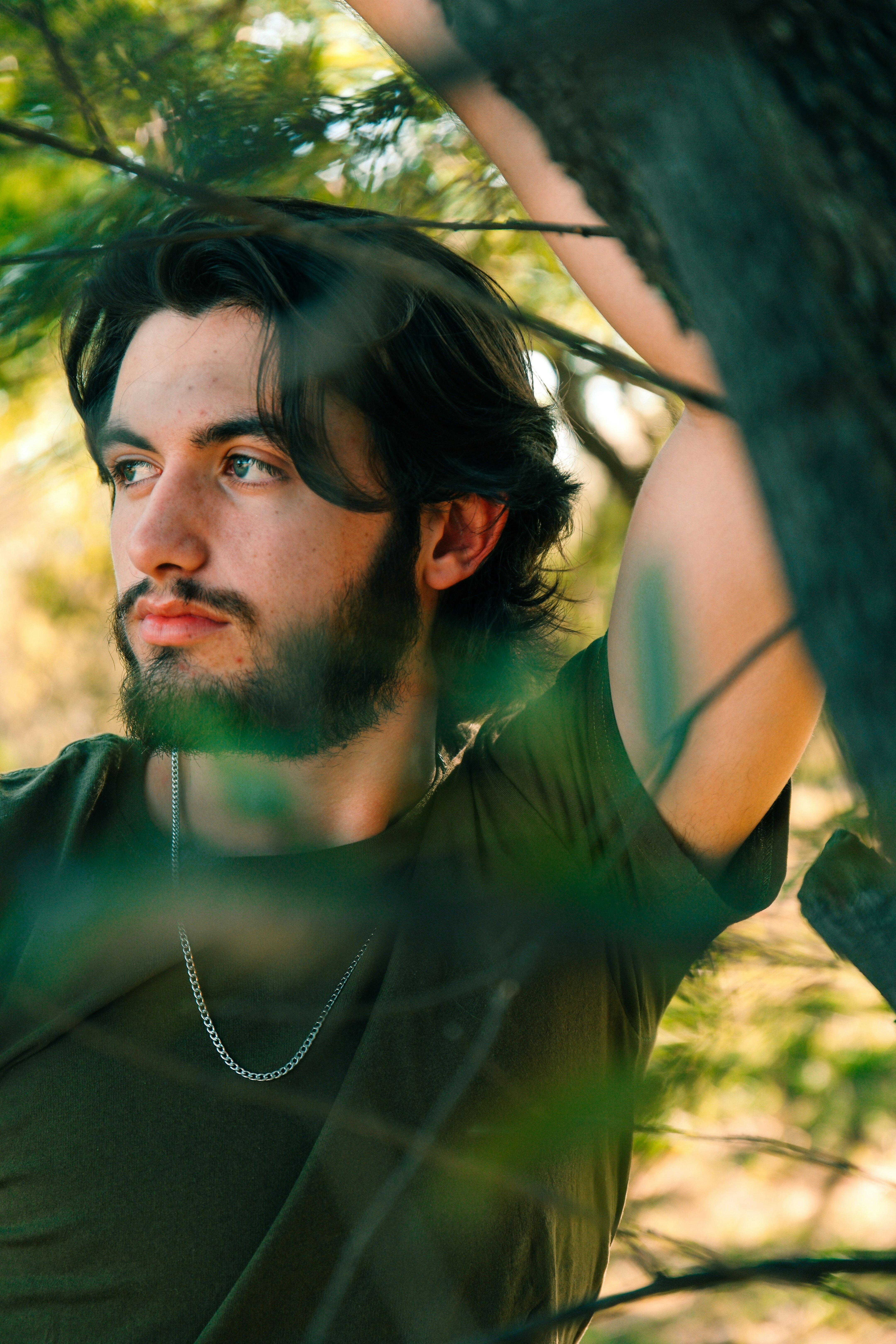 Handsome Male Model Standing in Bushes with Blurred Leaves in the Foreground
