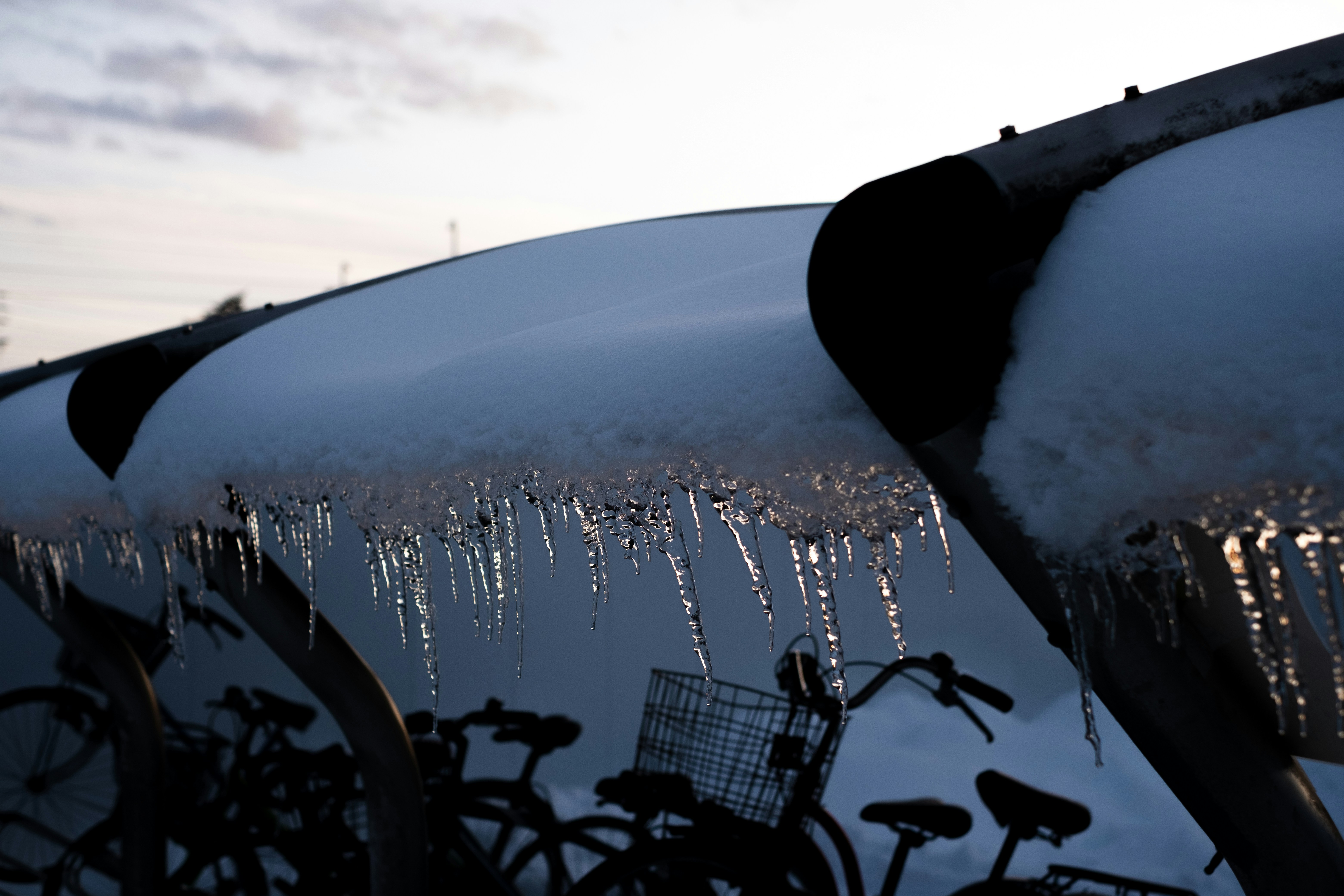 Icicles along Snow-Trimmed Bicycle Racks at Dusk