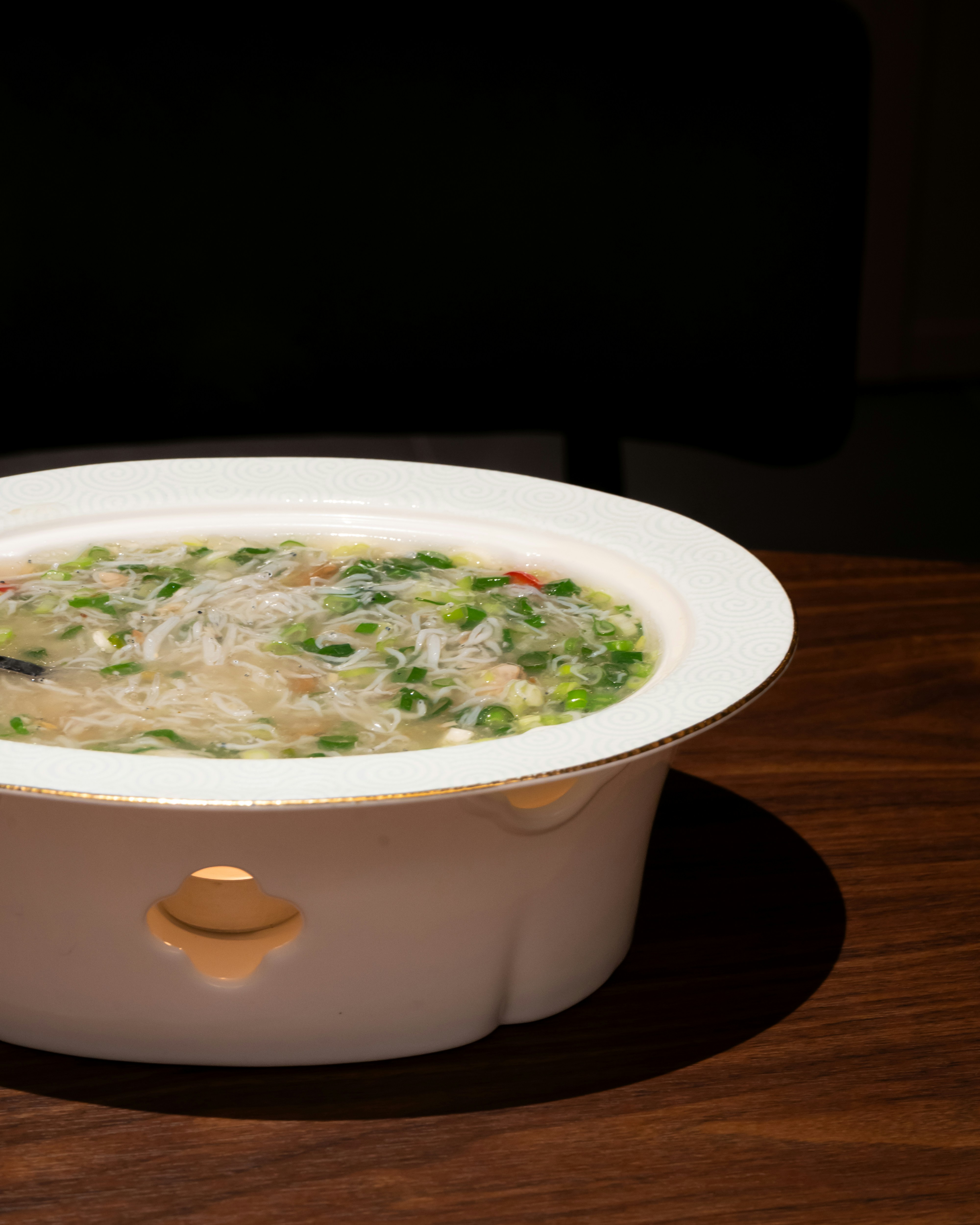 Warm Glow: White Ceramic Soup Warmer Illuminated on Wood