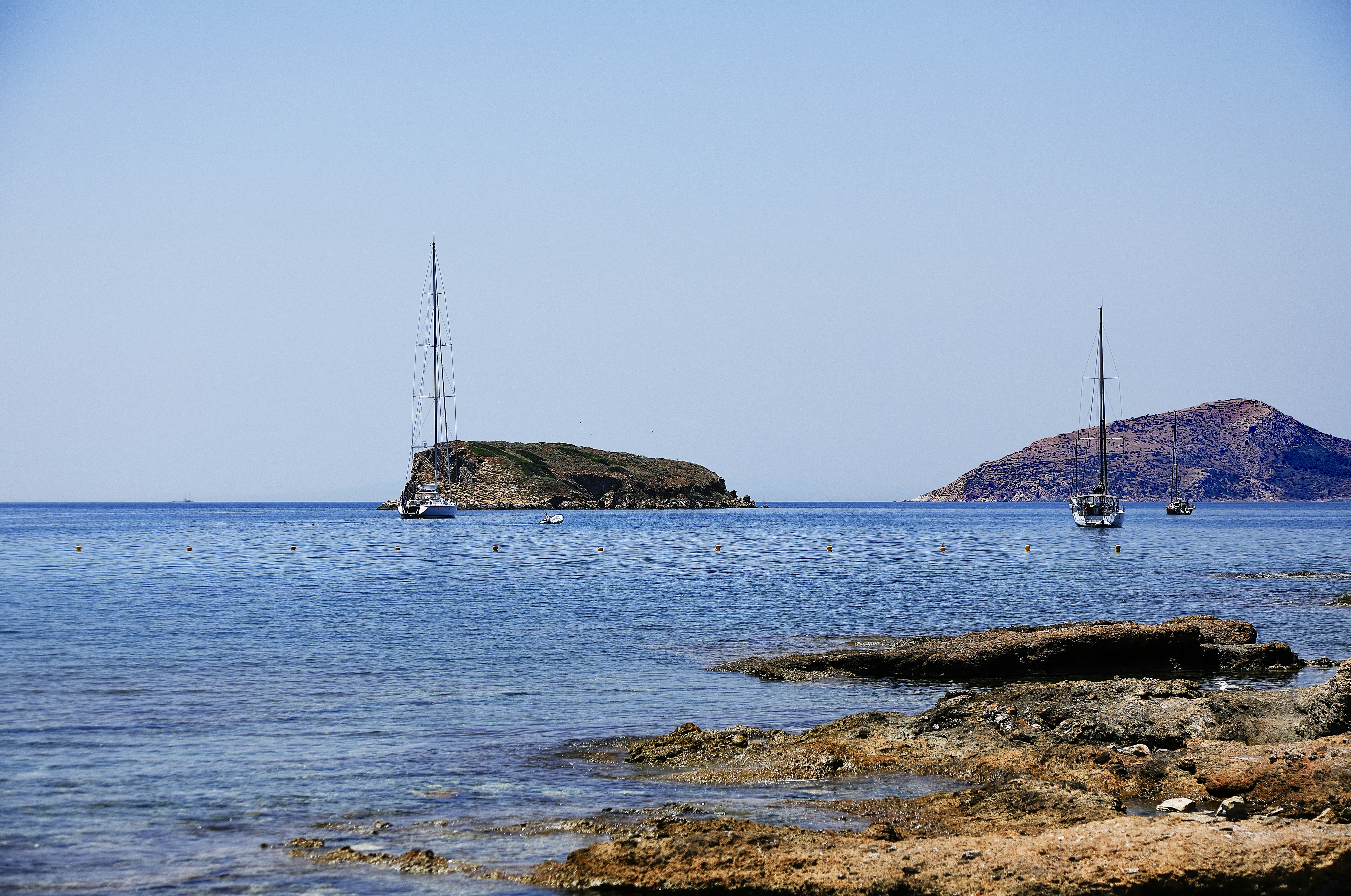 Masts at Distant Isle: A Quiet Seascape of Rock and Sail