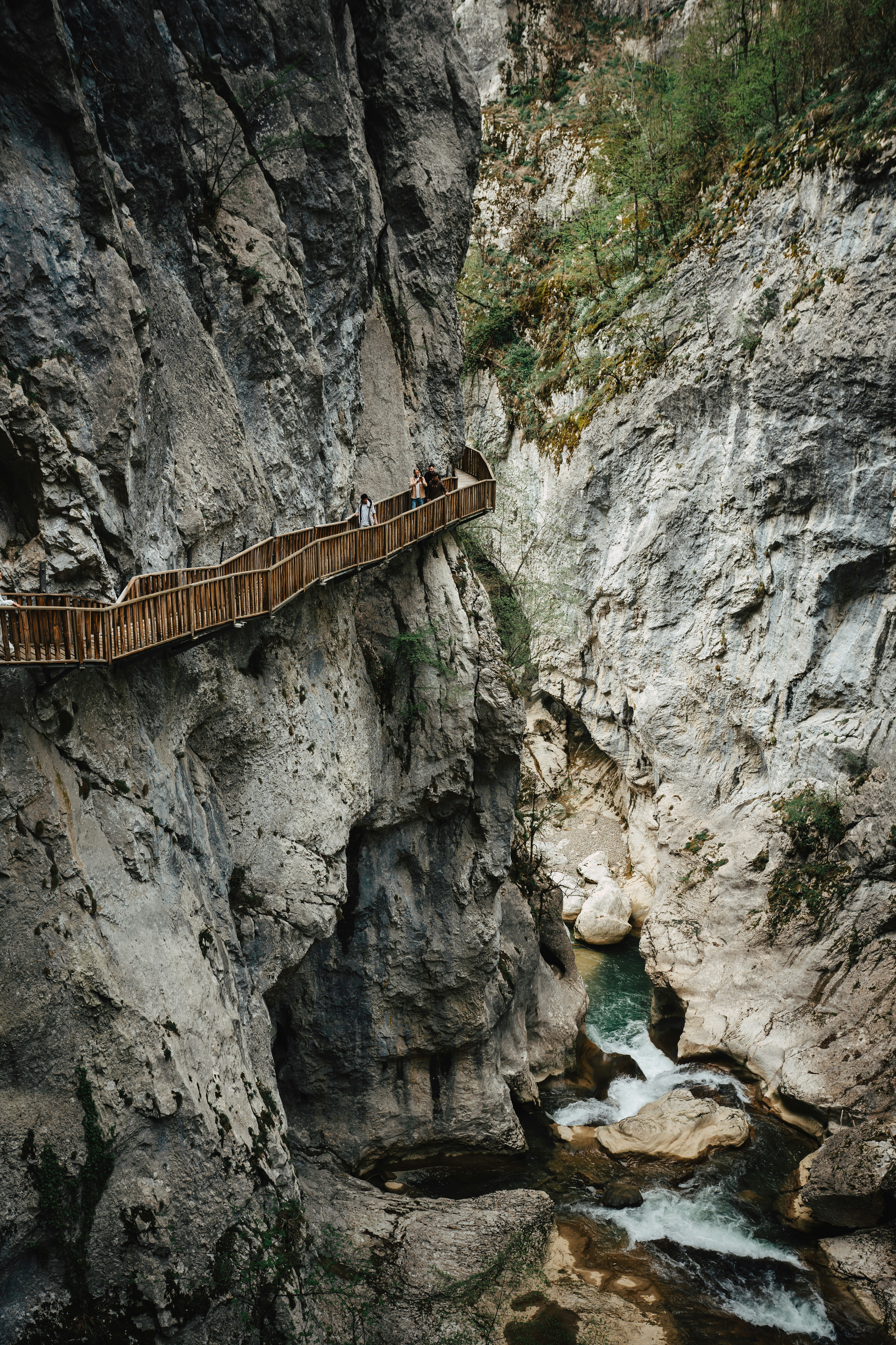 a wooden bridge over a river in a canyon
