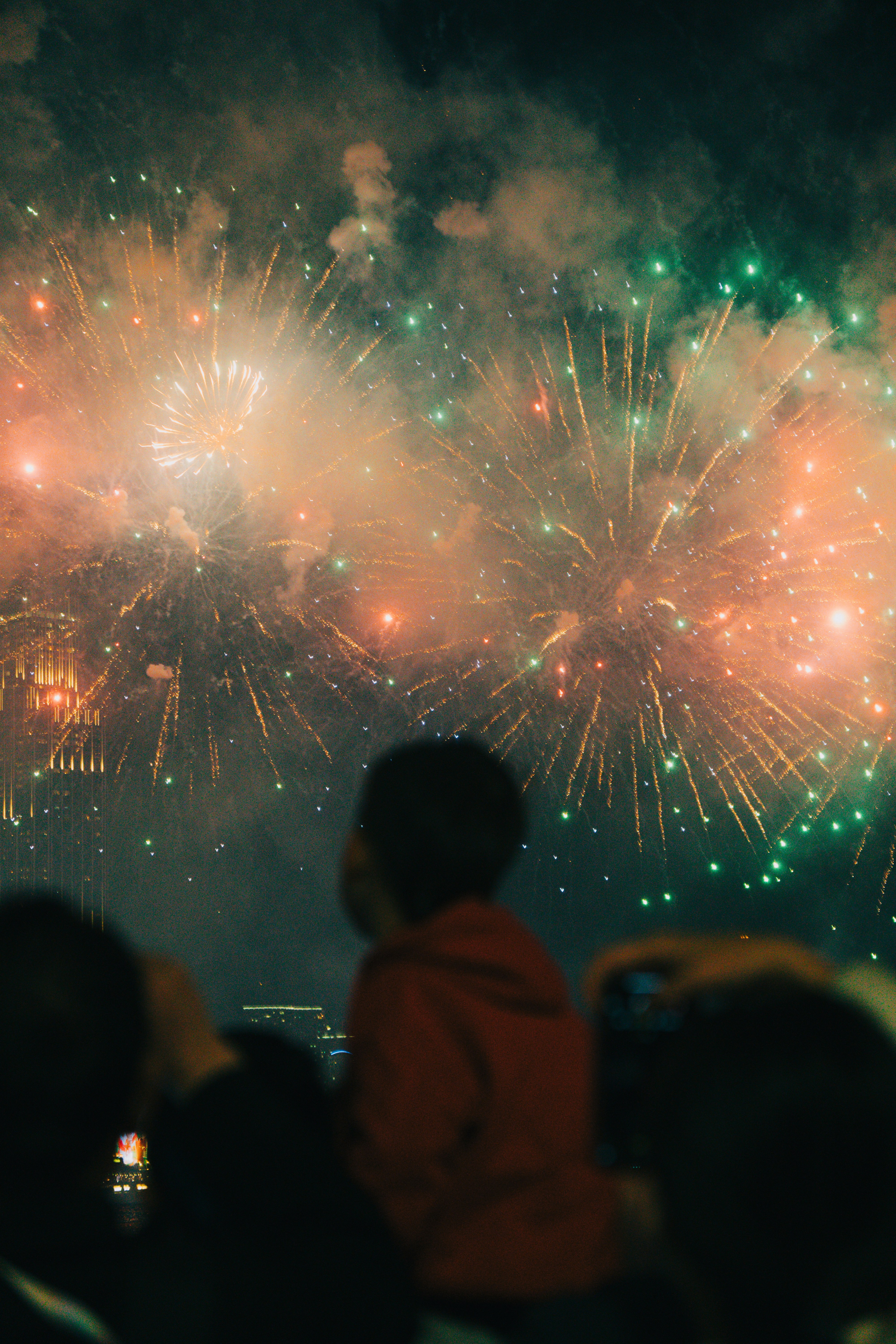 Emerald and Amber Fireworks Over a Silhouetted Night Crowd