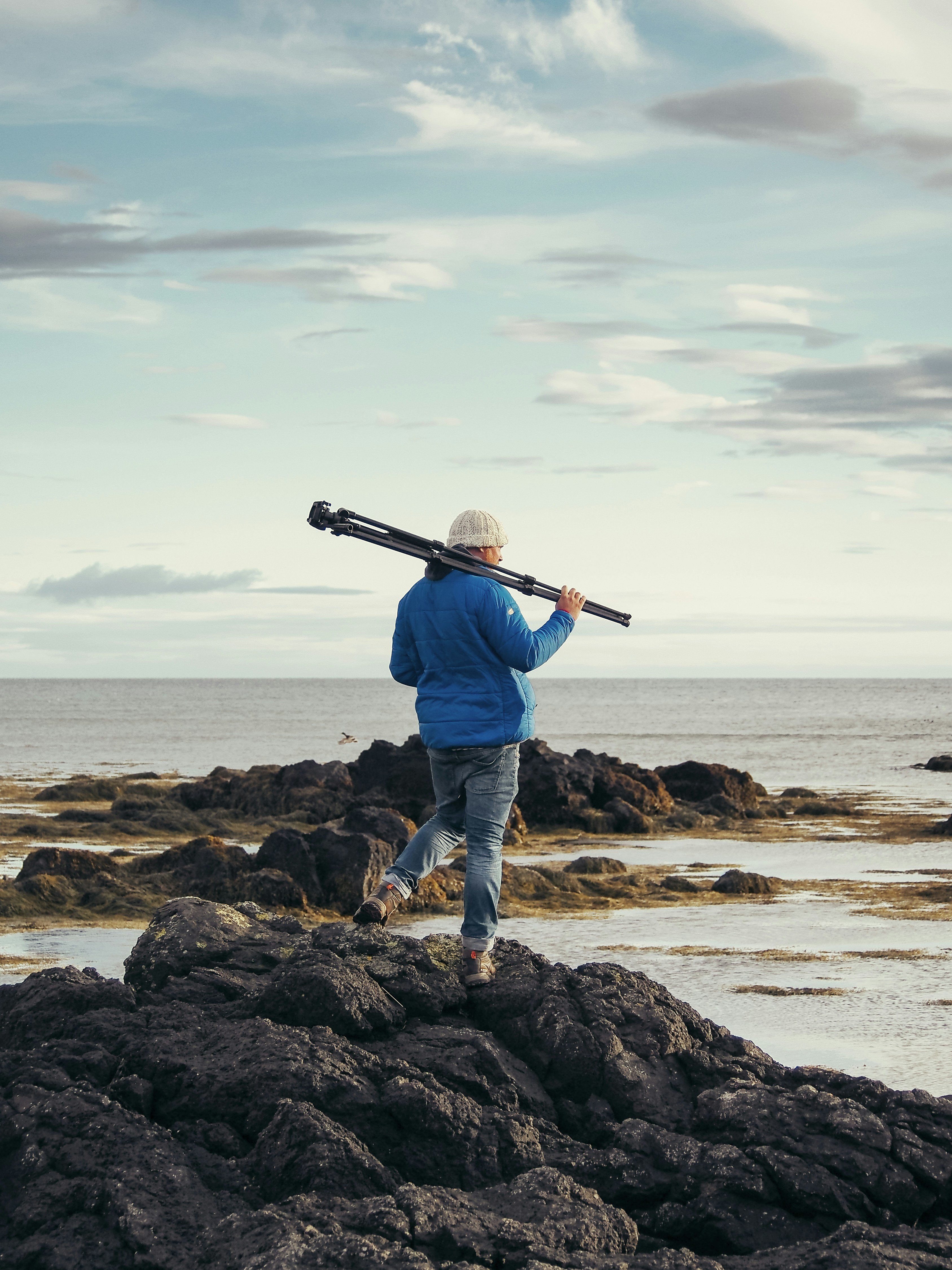 Rugged shoreline Trek: A Photographer Steps Between Sea and Lava