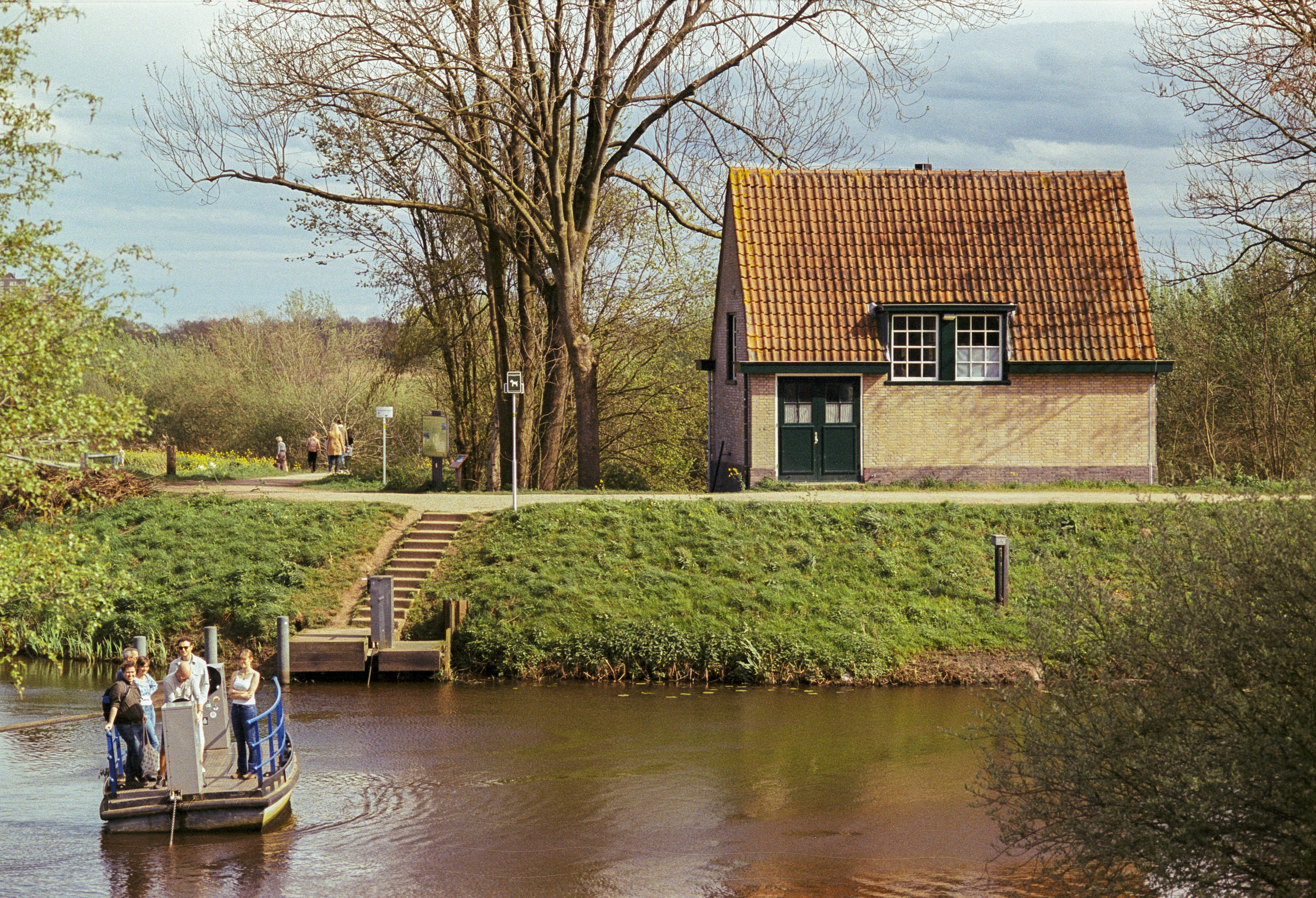 Red-Tiled Riverside Cottage Framed by a Quiet Boat Scene