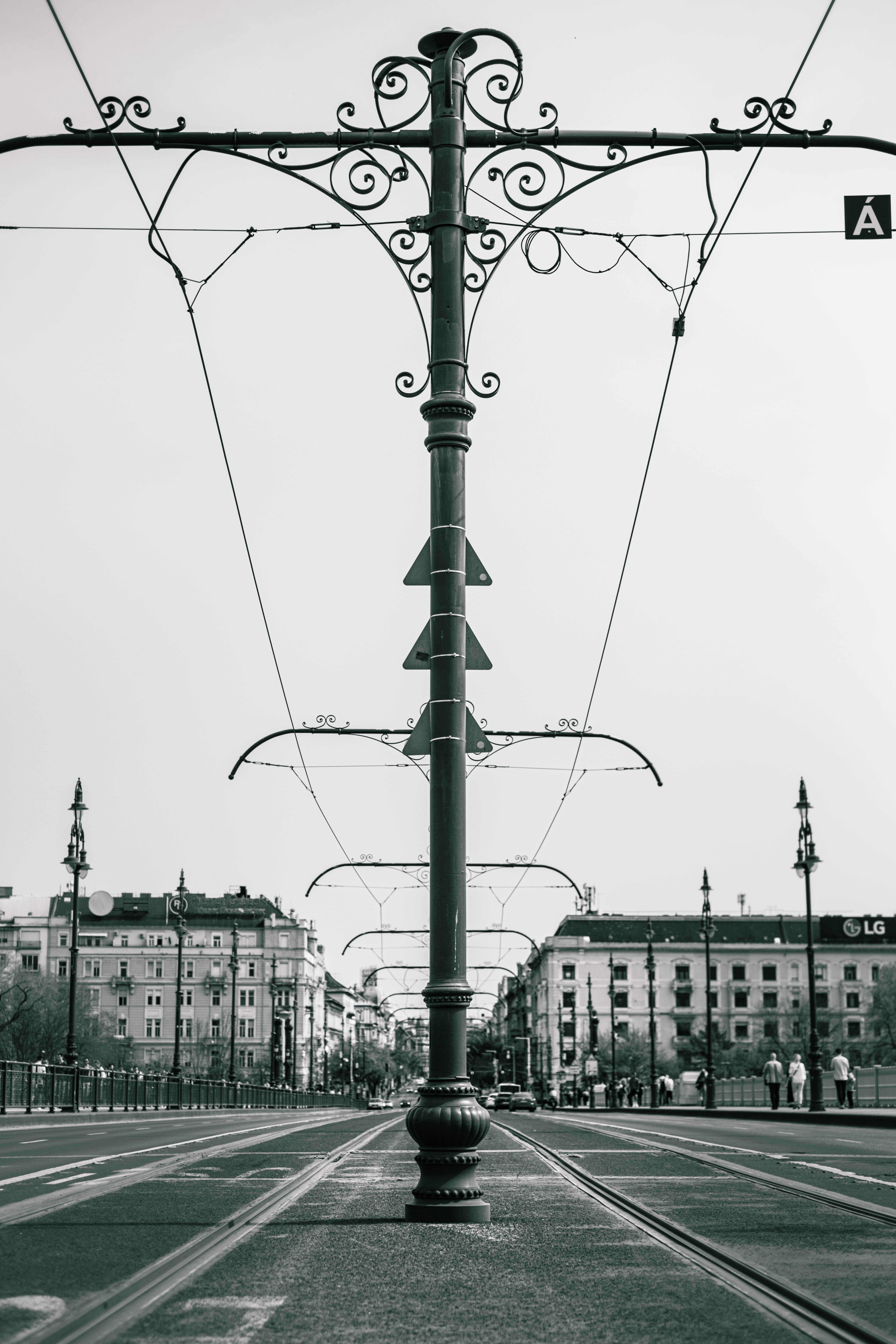 Straight Spine of the City: A Central Tramway Pole Framing the Quiet Boulevard