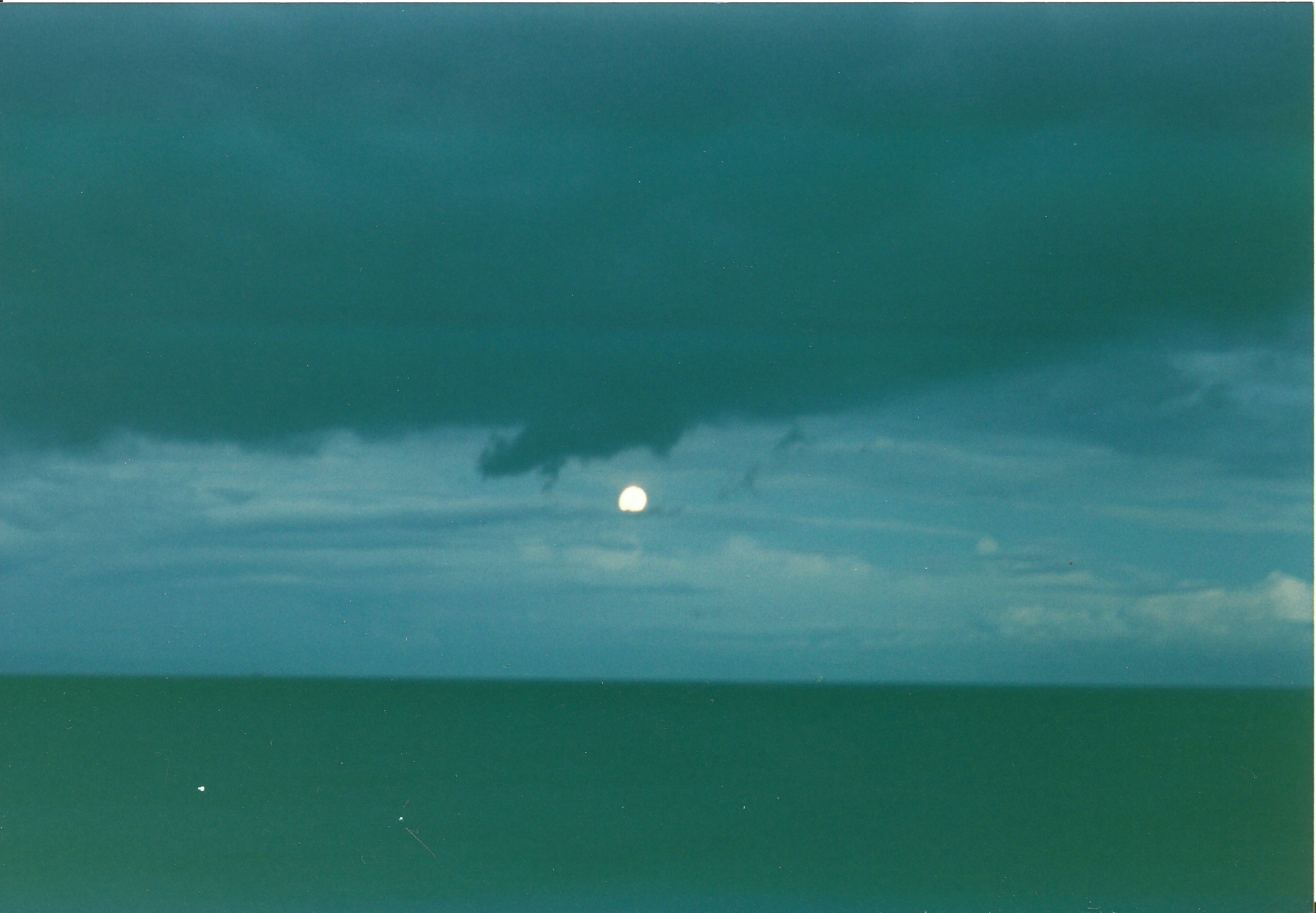 A full moon is seen in the distance over the ocean photo – Free Analog ...