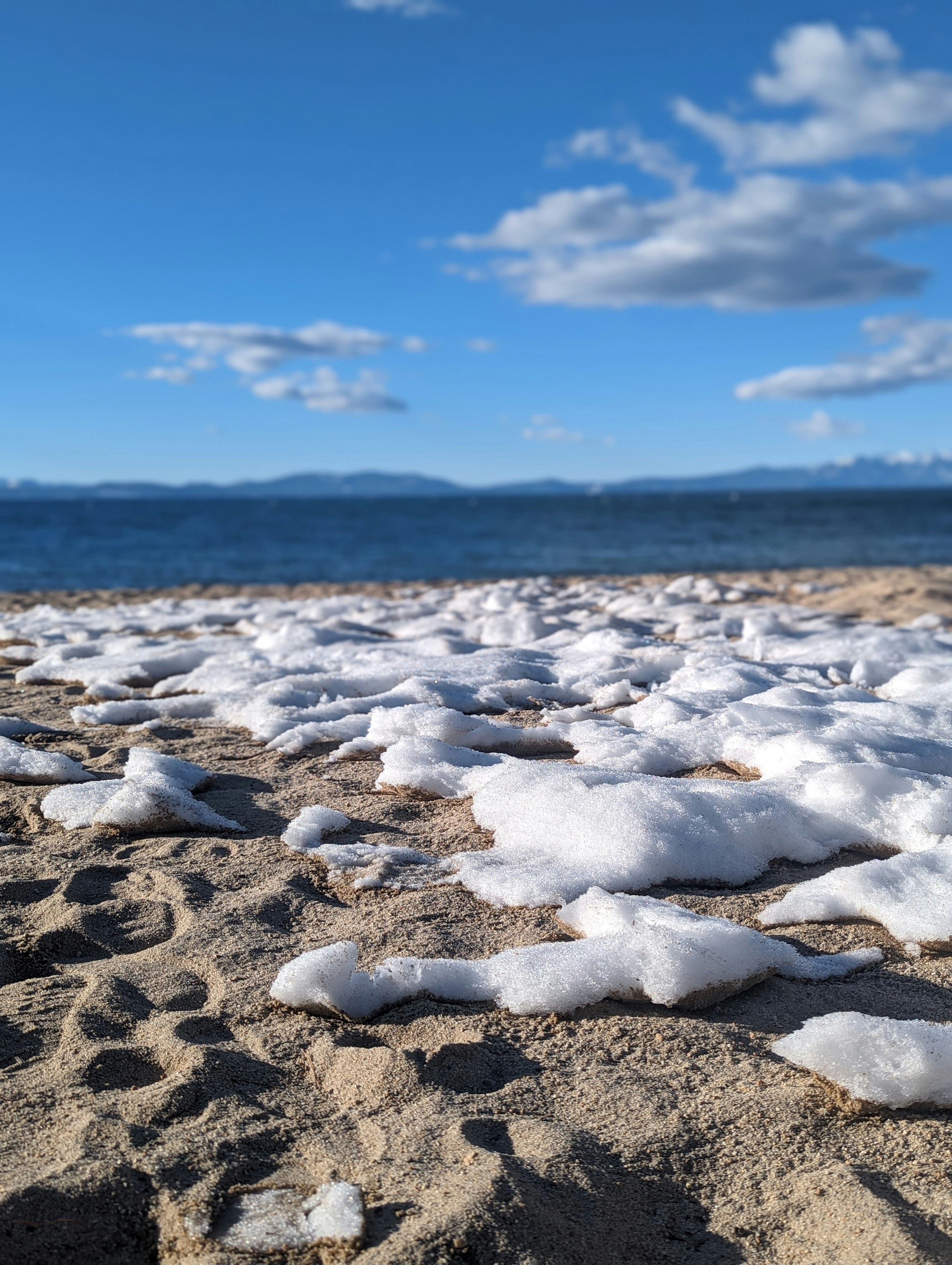 A sandy beach covered in snow under a blue sky photo – Free Nature ...